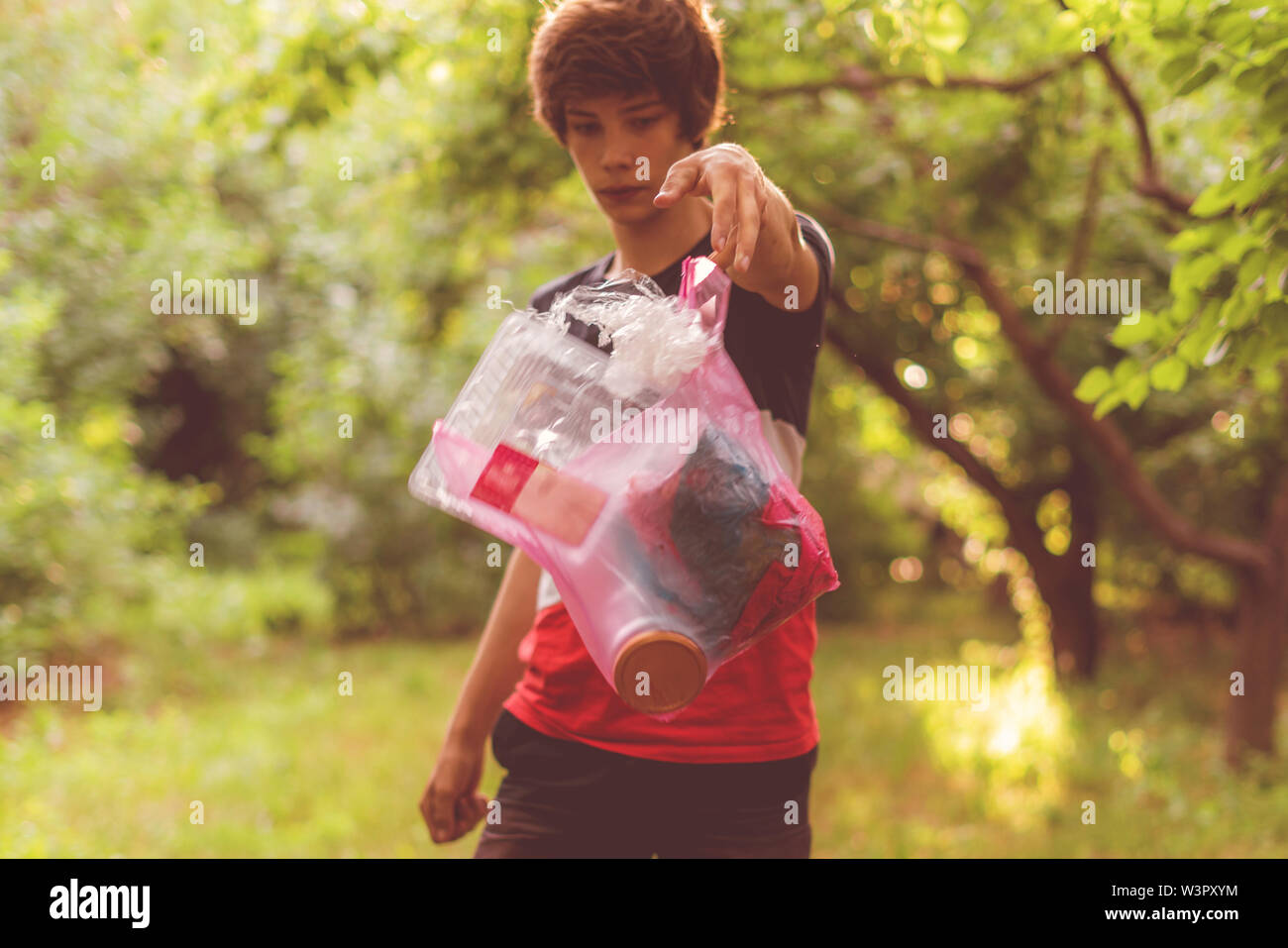 young person throw the plastic package with trash away in the nature ...