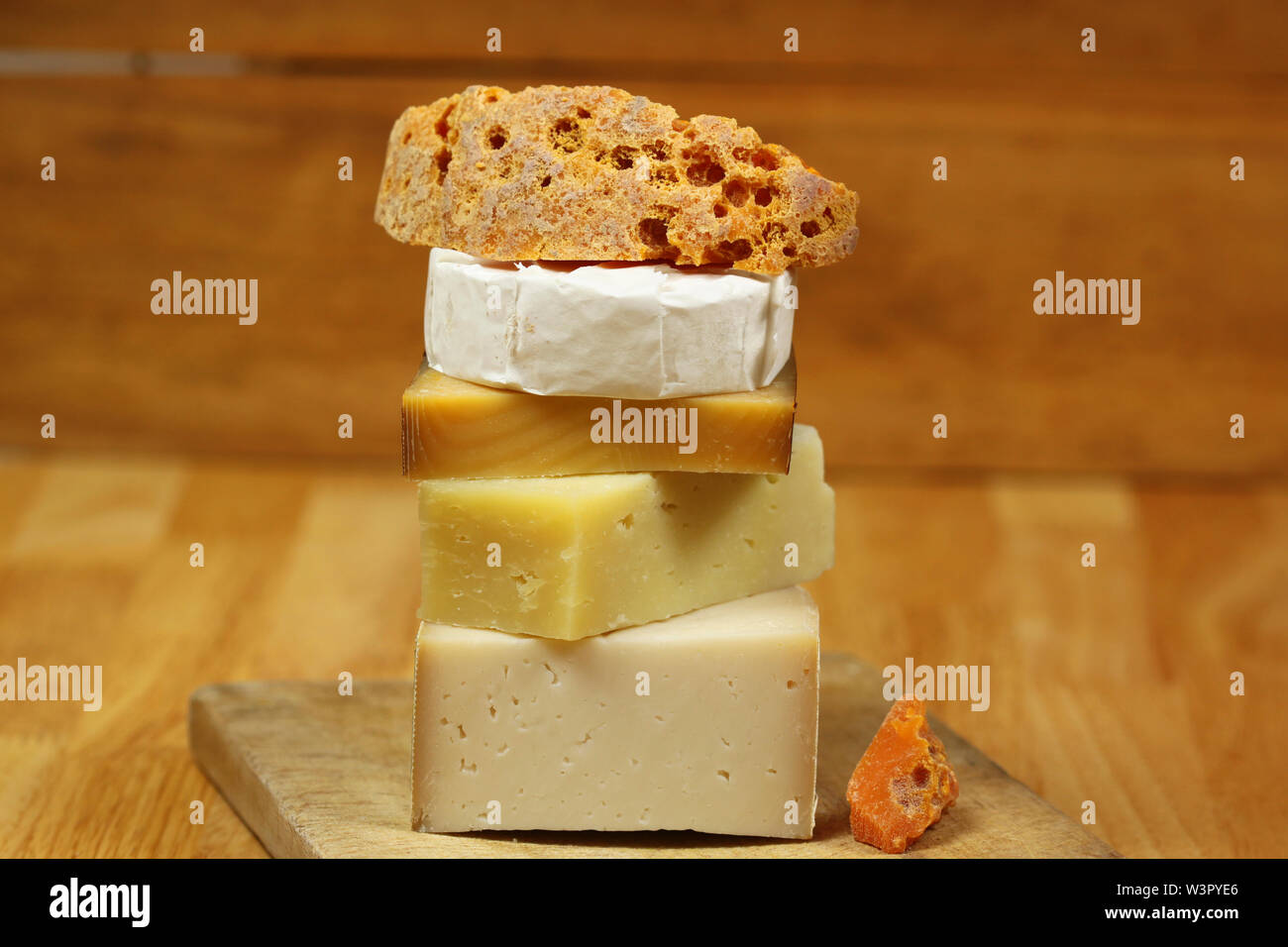 Stack of different kinds of cheese on wooden board - goat cheese ...