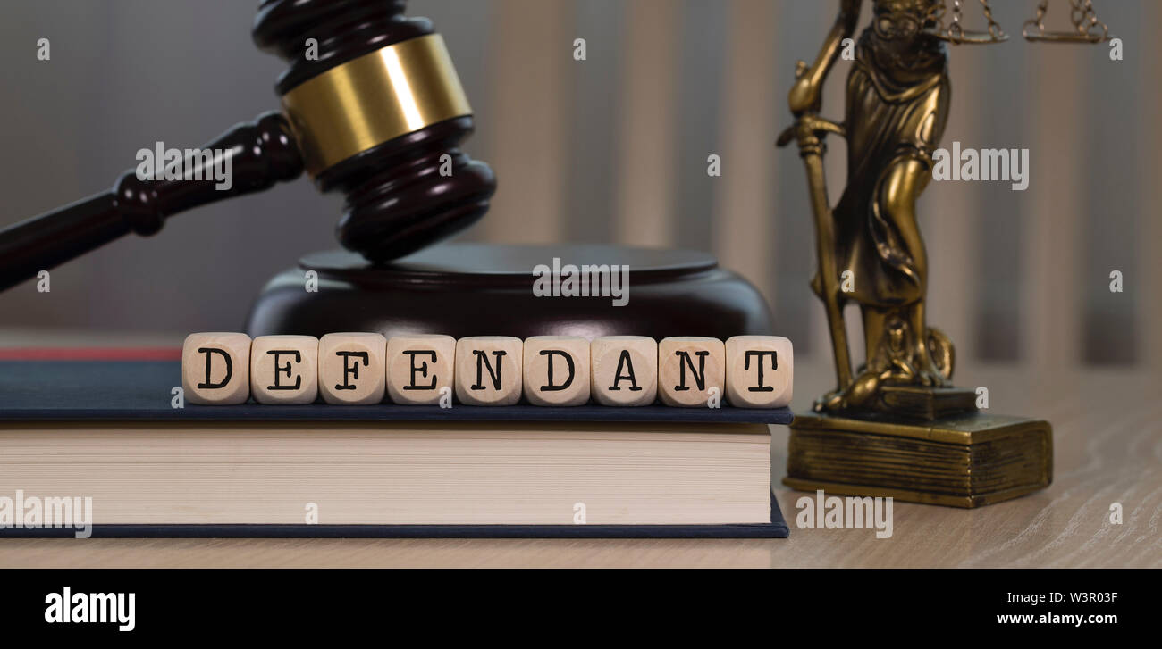 Word DEFENDANT composed of wooden dices. Wooden gavel and statue of ...