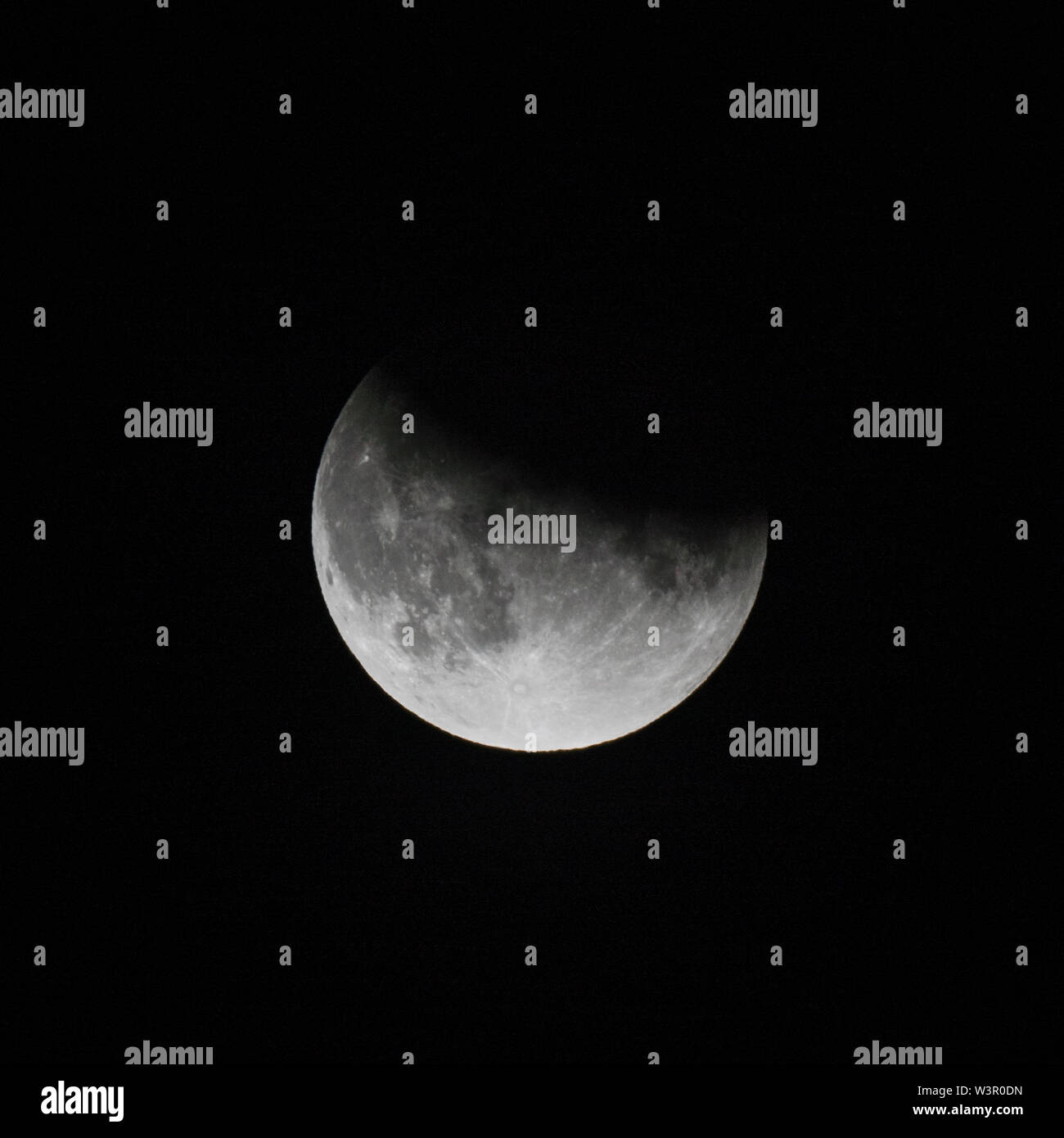 close up view of a partial lunar eclipse in the black night sky in July ...