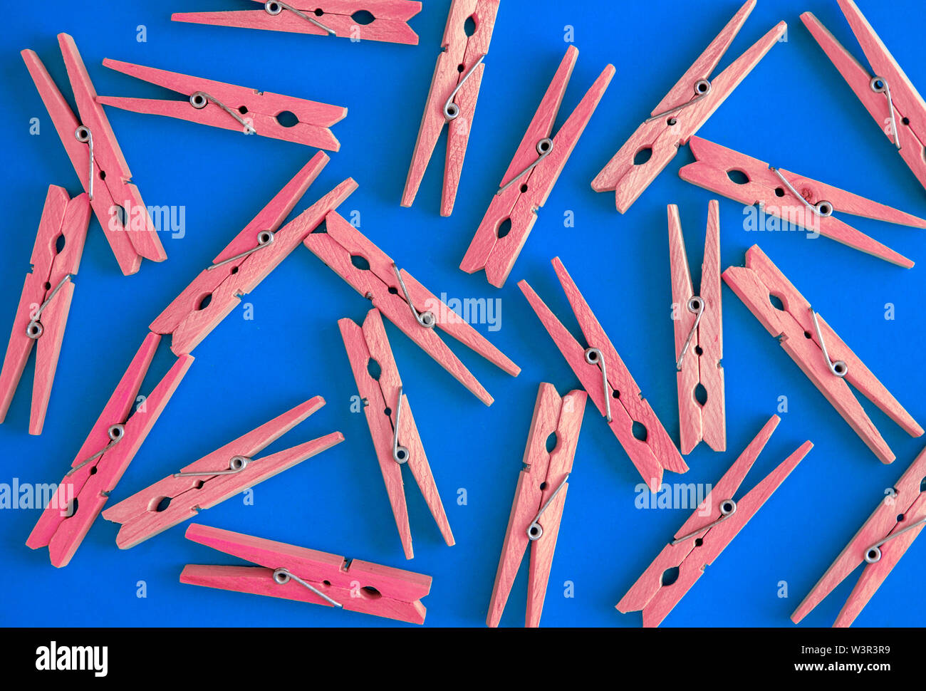 Wooden red clothespins are scattered on a blue-cyan-green background ...