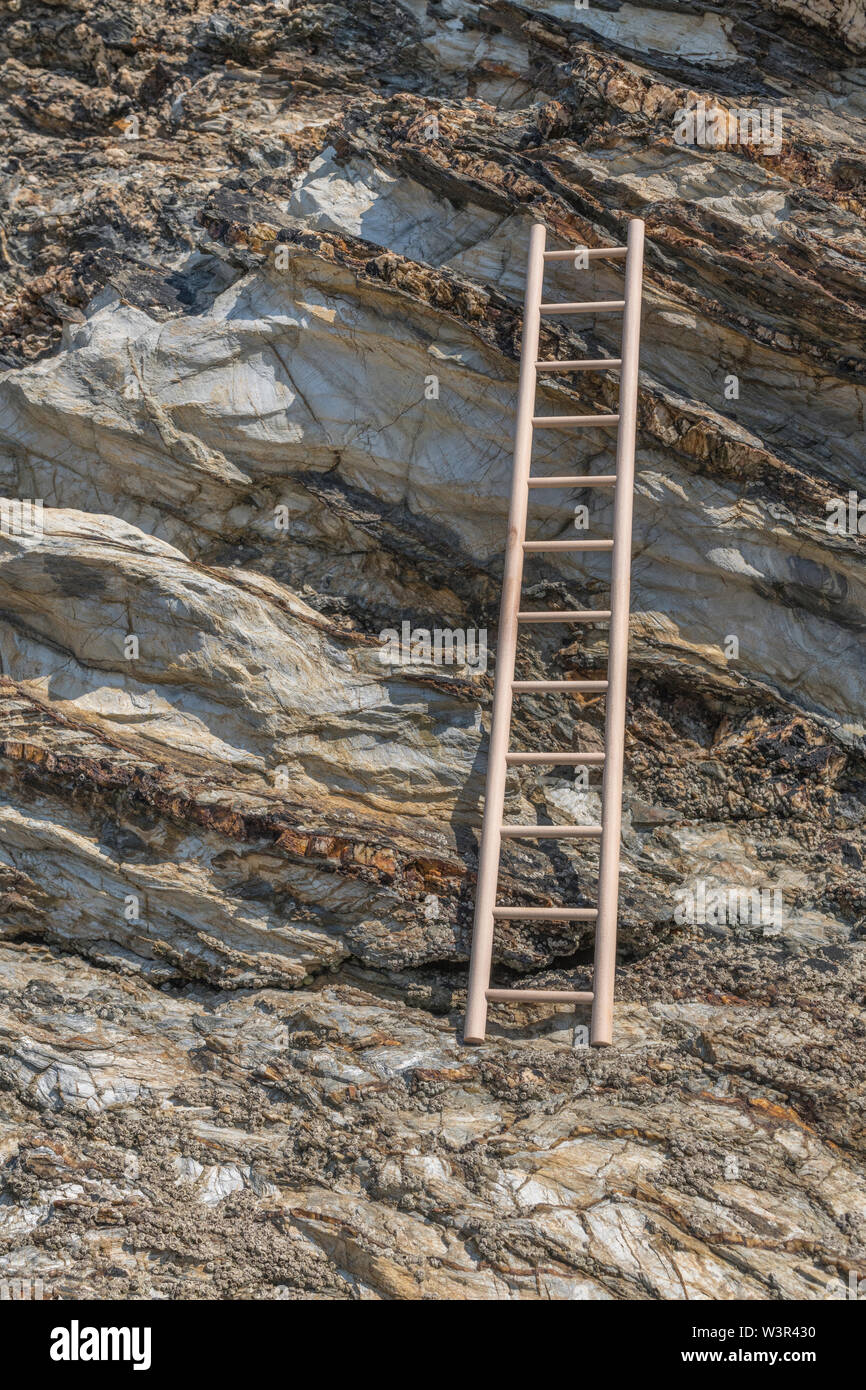 Small wood toy ladder propped against cliff face. Metaphor climbing ...
