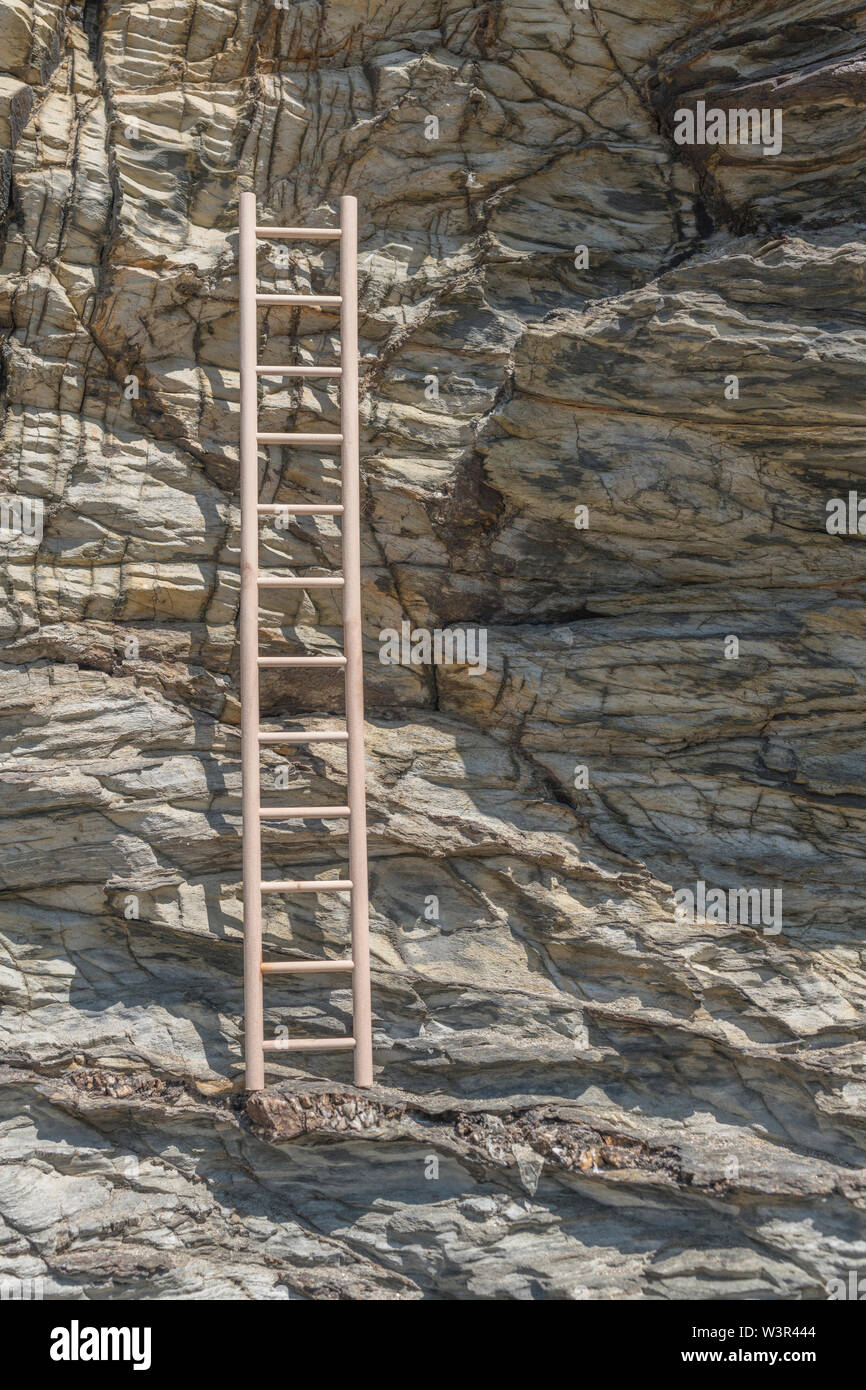 Small wood toy ladder propped against cliff face. Metaphor climbing ...