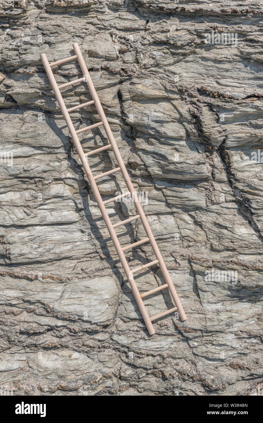 Small wood toy ladder propped against cliff face. Metaphor climbing ...
