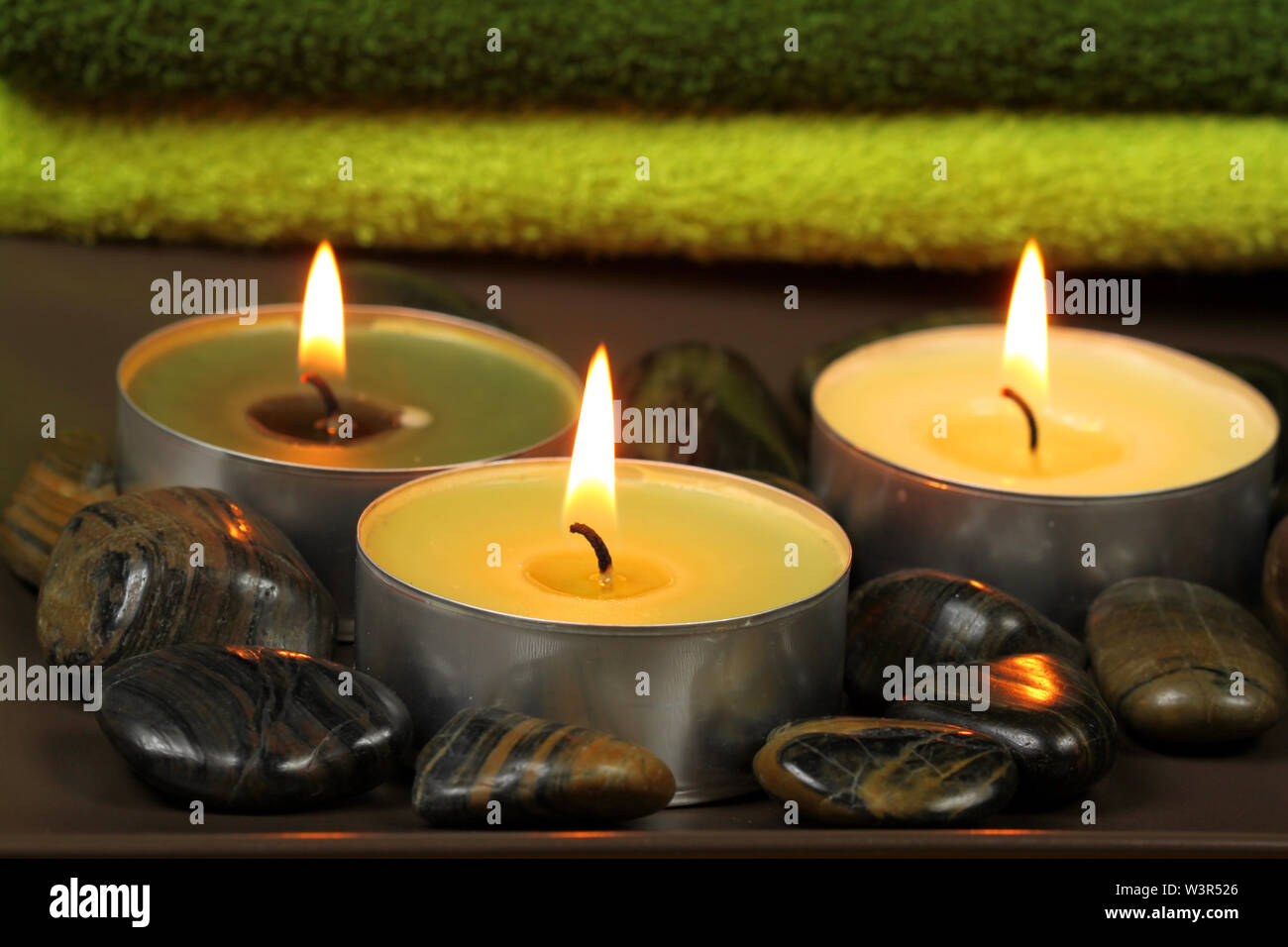 Green apple aromatised candles and pebbles. SPA therapy Stock Photo - Alamy