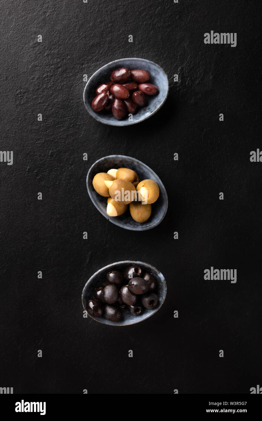 Various types of olives in bowls, shot from the top on a black ...