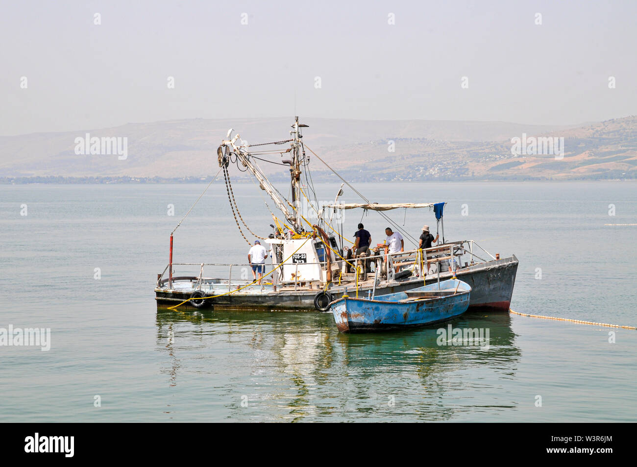 fishing boat and dinghy rounding up fish in a net the Sea of Galilee ...