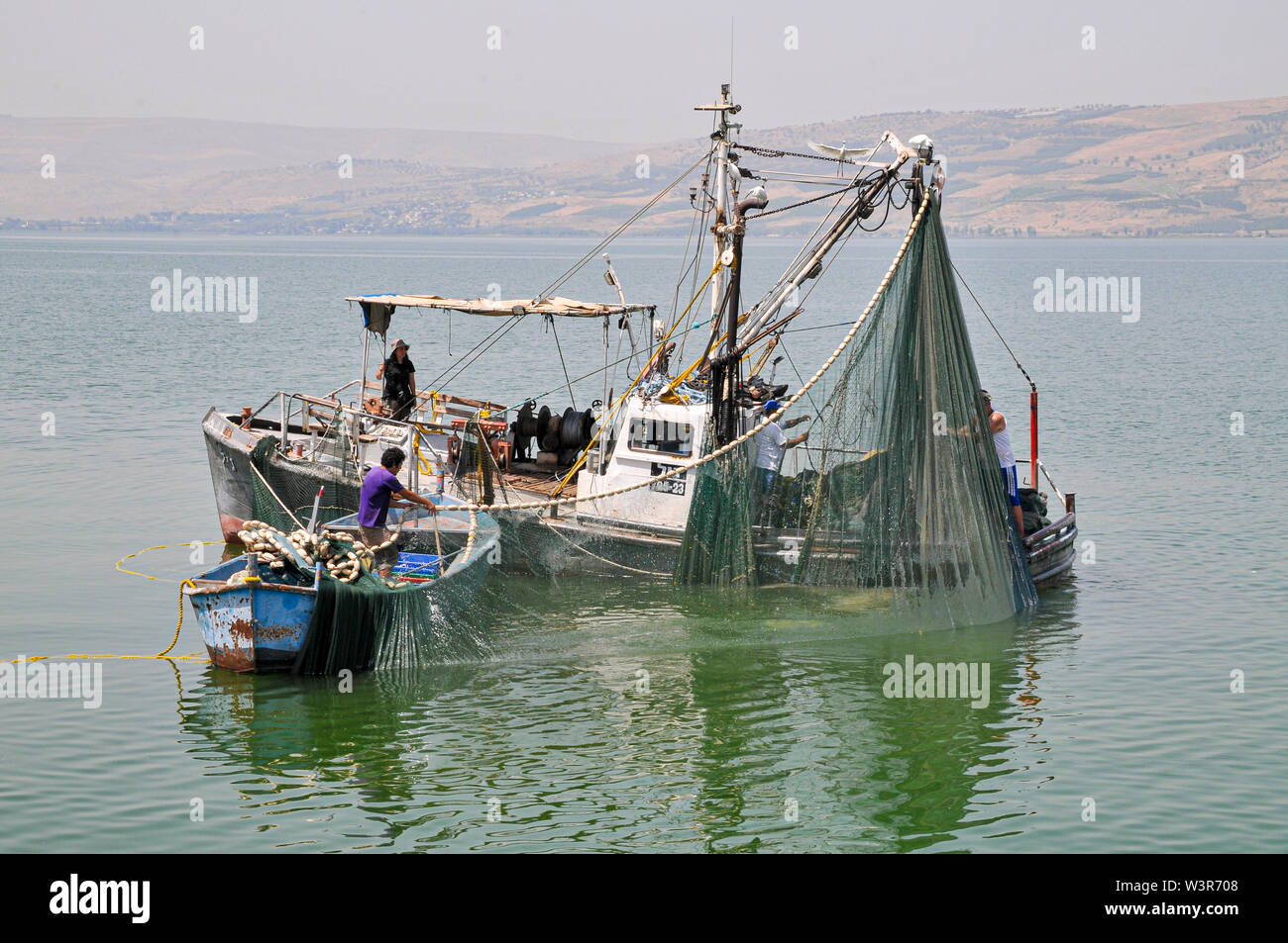 fishing boat rounding up fish in a net the Sea of Galilee, Israel Stock ...