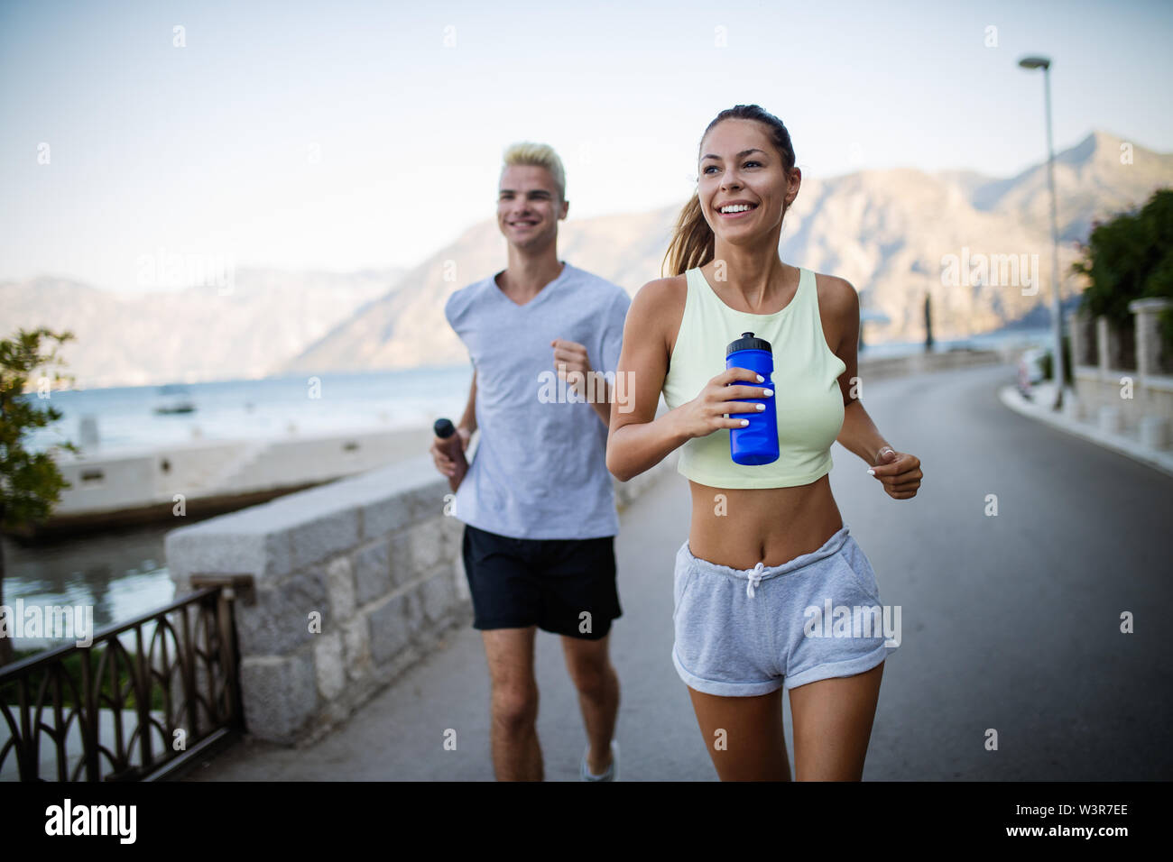 Happy young fit people couple running outdoor Stock Photo - Alamy