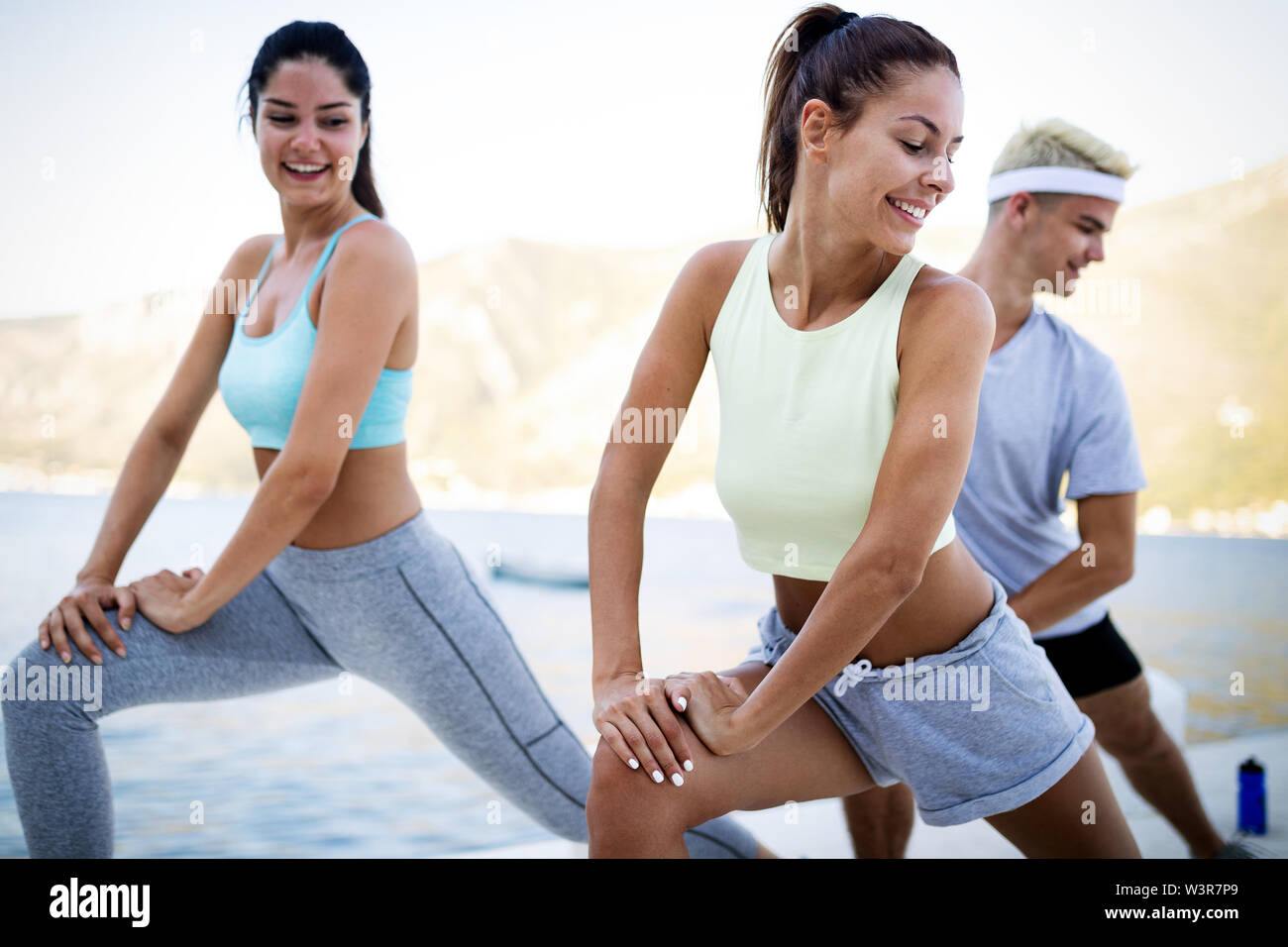 Fit group of happy people exercising outdoor. Smiling friends doing ...