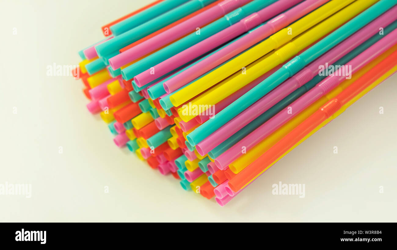 Colorful single-use plastic drinking straws spread on a white ...