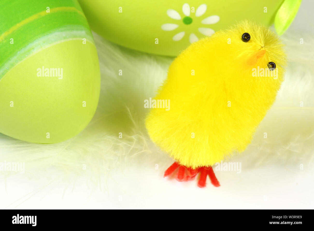 A cute yellow chick with green Easter eggs on soft feather Stock Photo ...