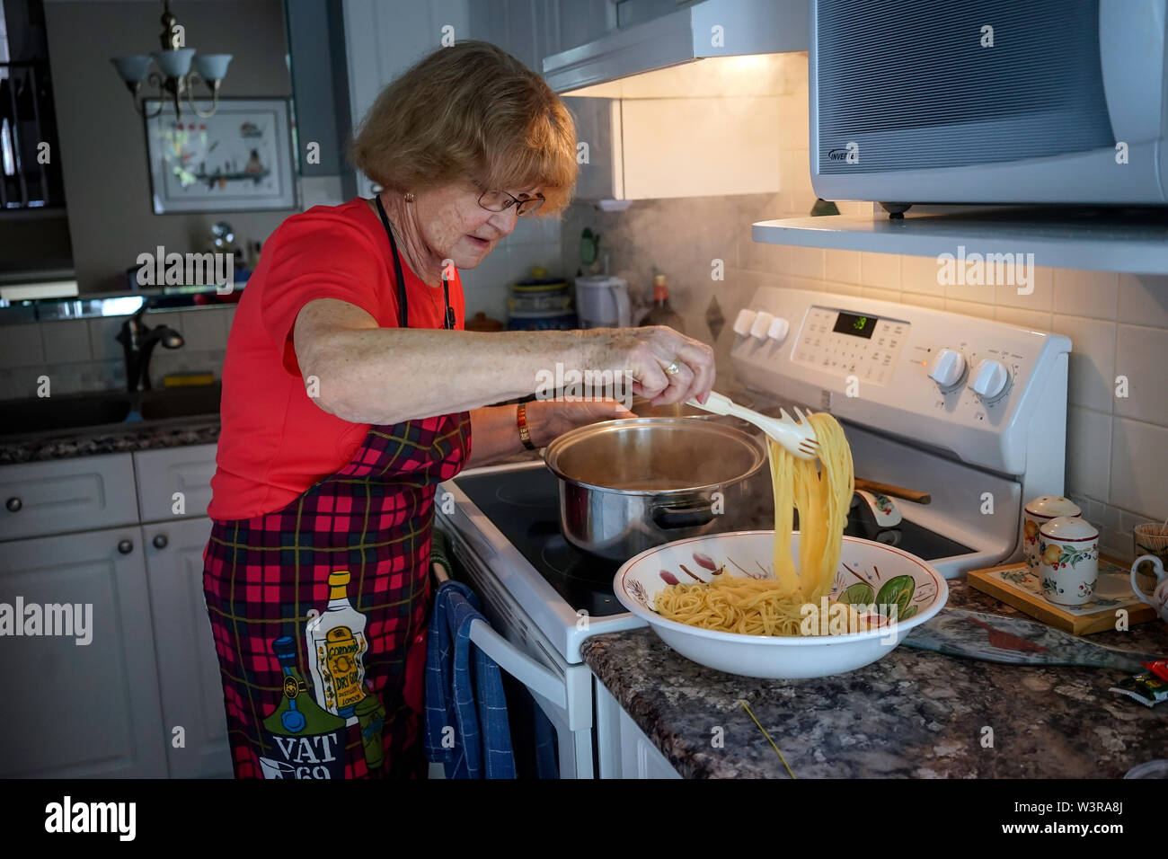 Mature Women is cooking a Italian Spaghetti Dinner in her home kitchen ...
