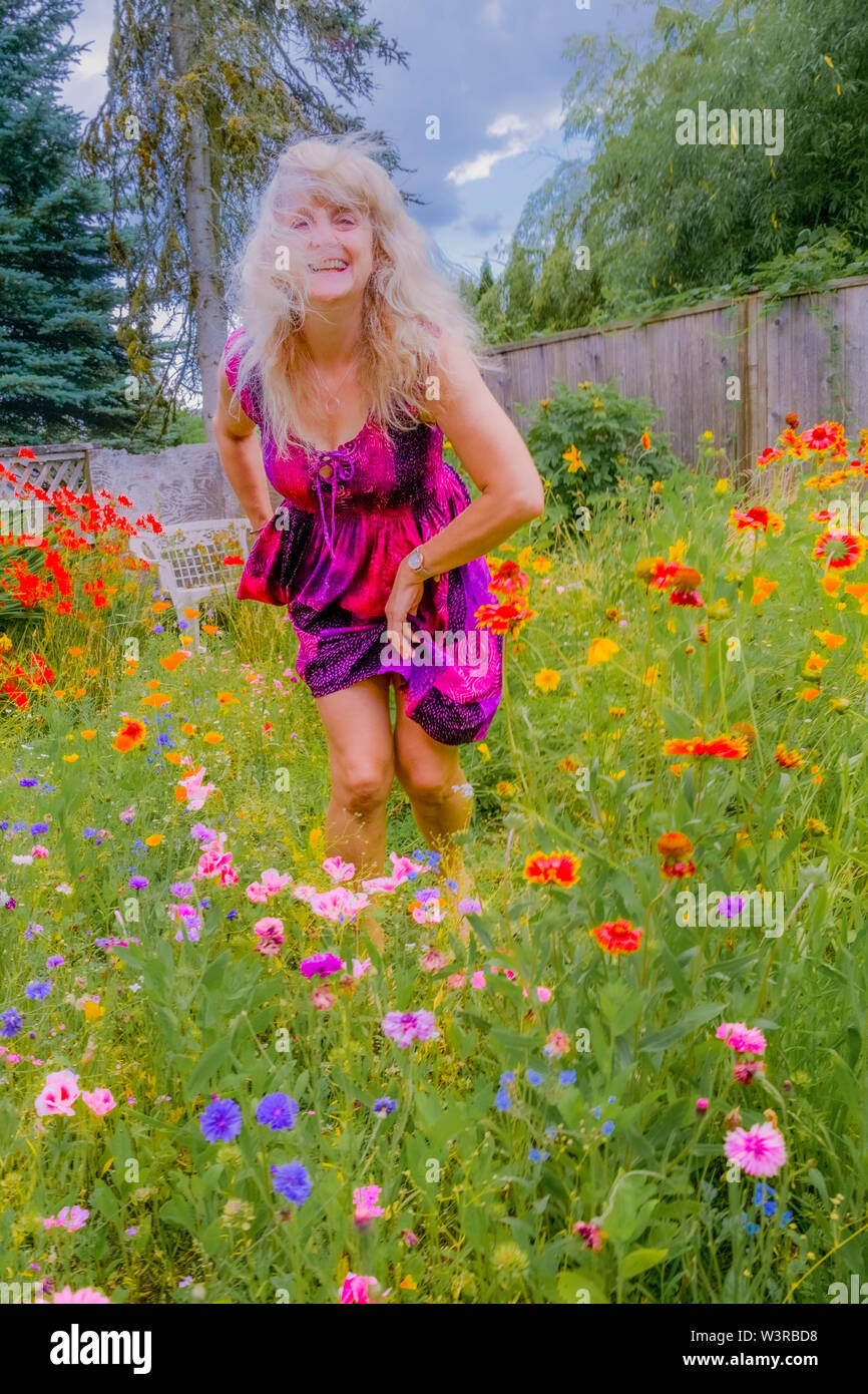 Blonde woman dancing in her backyard full of wildflowers Stock Photo ...