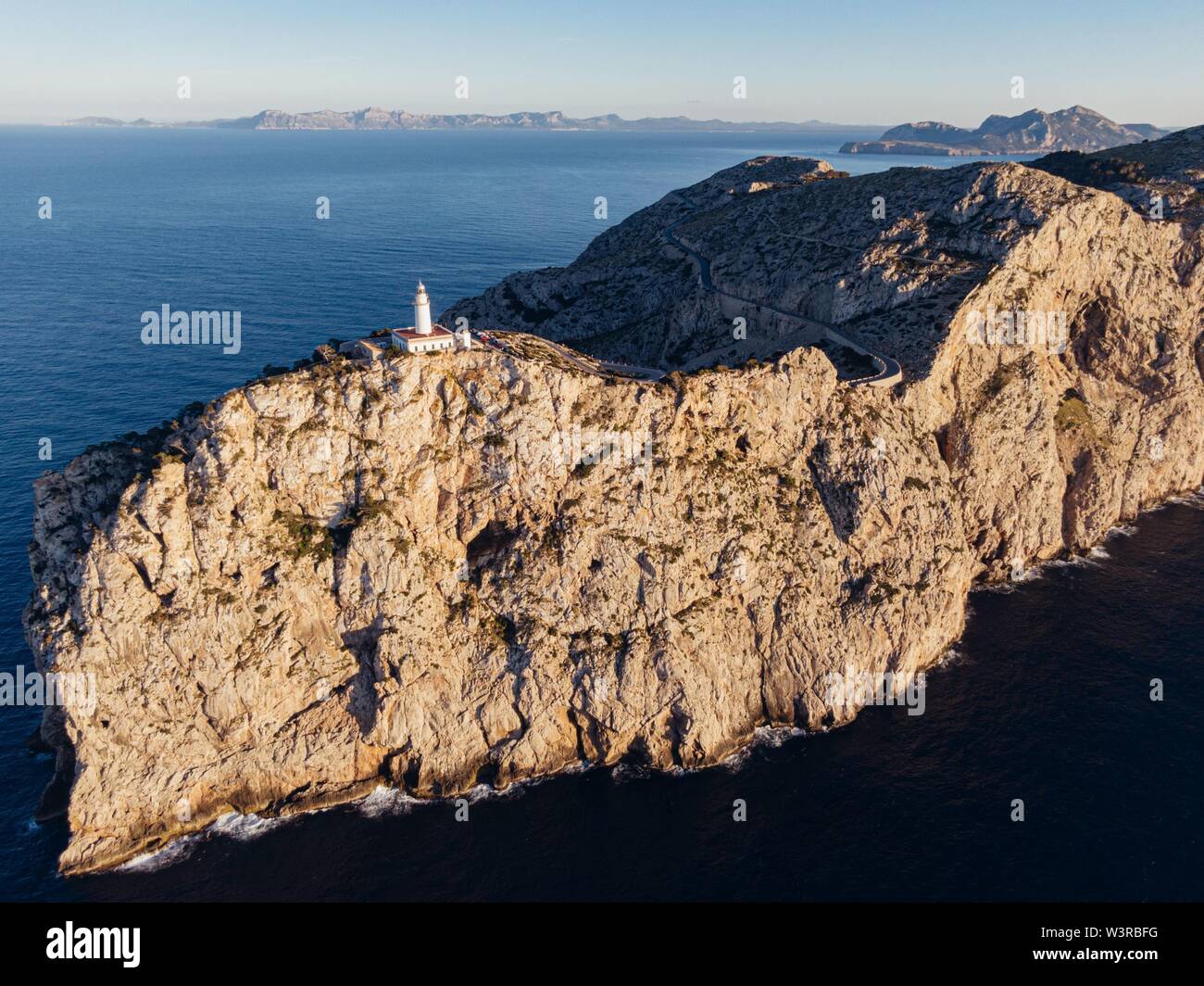 Aerial distant shot of a high rocky cliff with a white tower built on ...