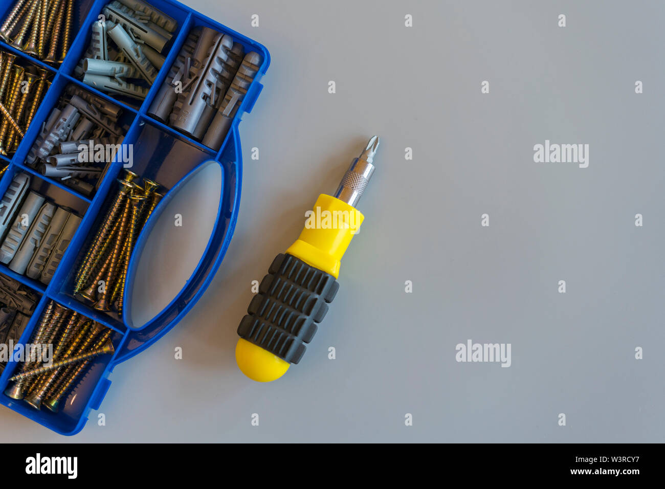 Tool box with screws, various types of parts and screwdrivers On a gray ...