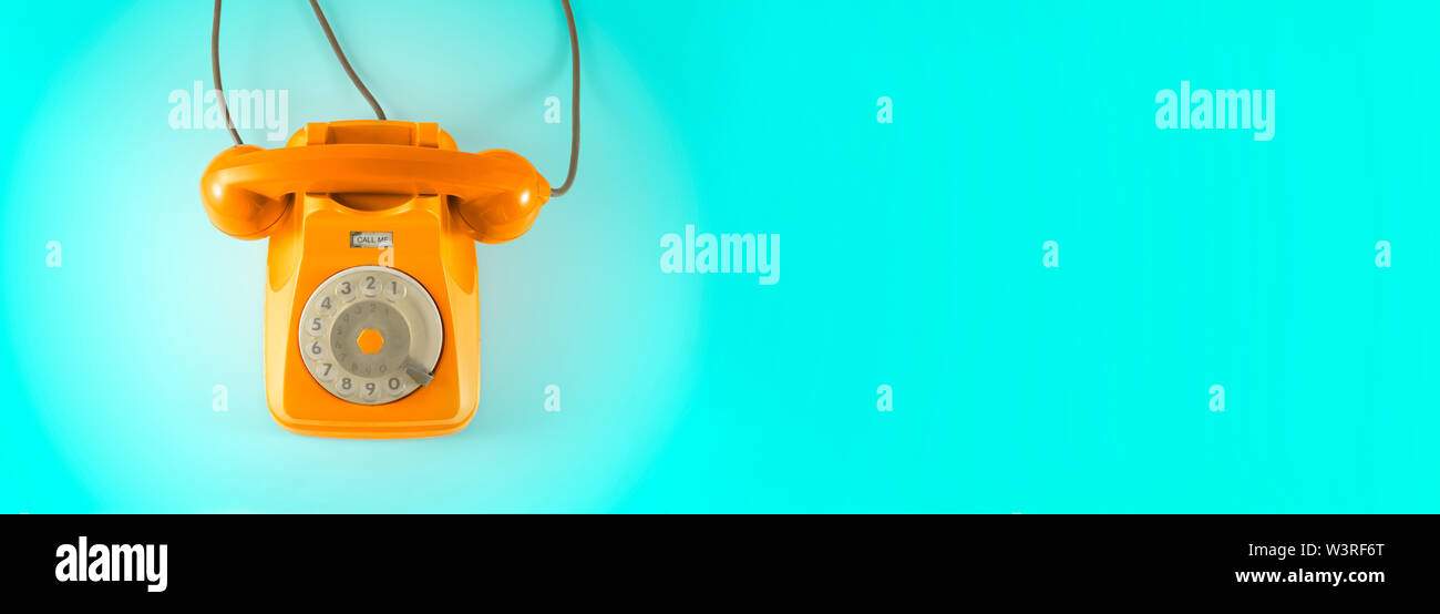 A orange vintage dial telephone with blue background Stock Photo - Alamy