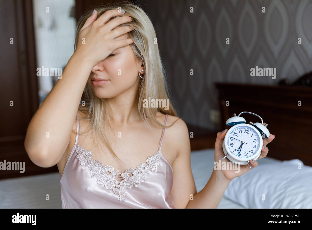 Beautiful young woman wake up in morning annoyed alarm clock holding ...