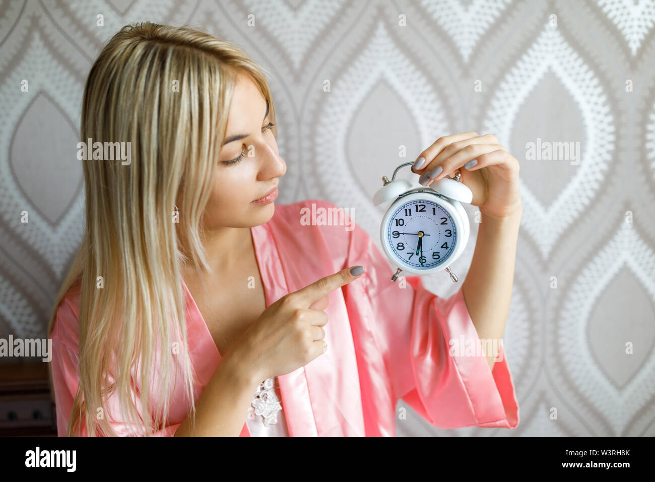 Beautiful young woman wake up in morning annoyed alarm clock holding ...