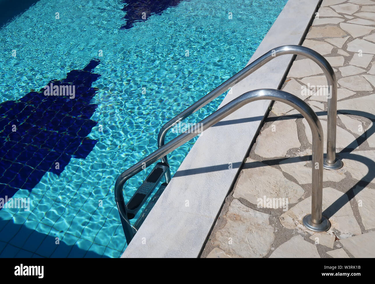 Metal stainless steel ladder in summer blue swimming pool Stock Photo ...