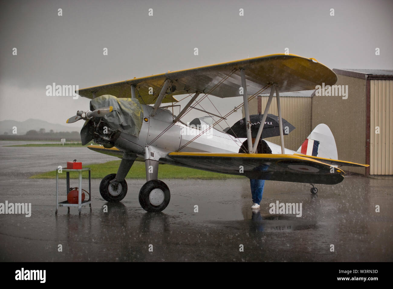 Man next to biplane in the rain Stock Photo - Alamy