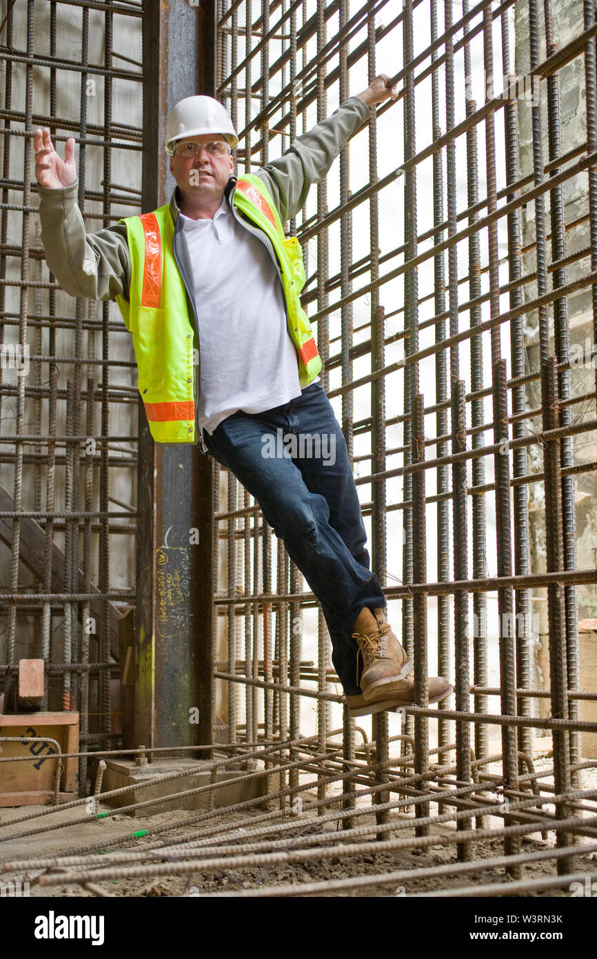 Portrait of a male construction worker hanging from a wire grid on a ...