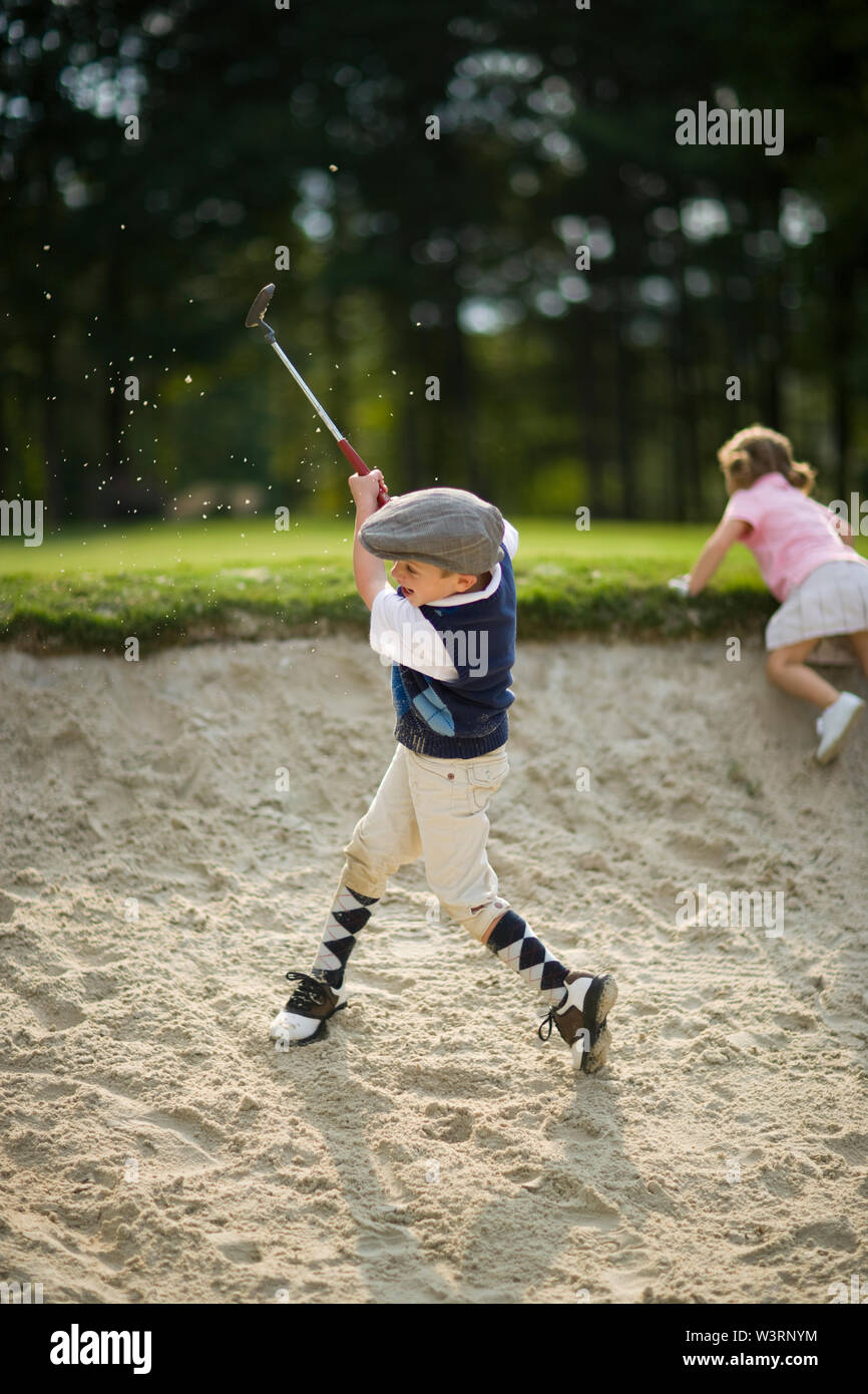 Young boy playing with a putter in a sandpit on a golf course Stock ...