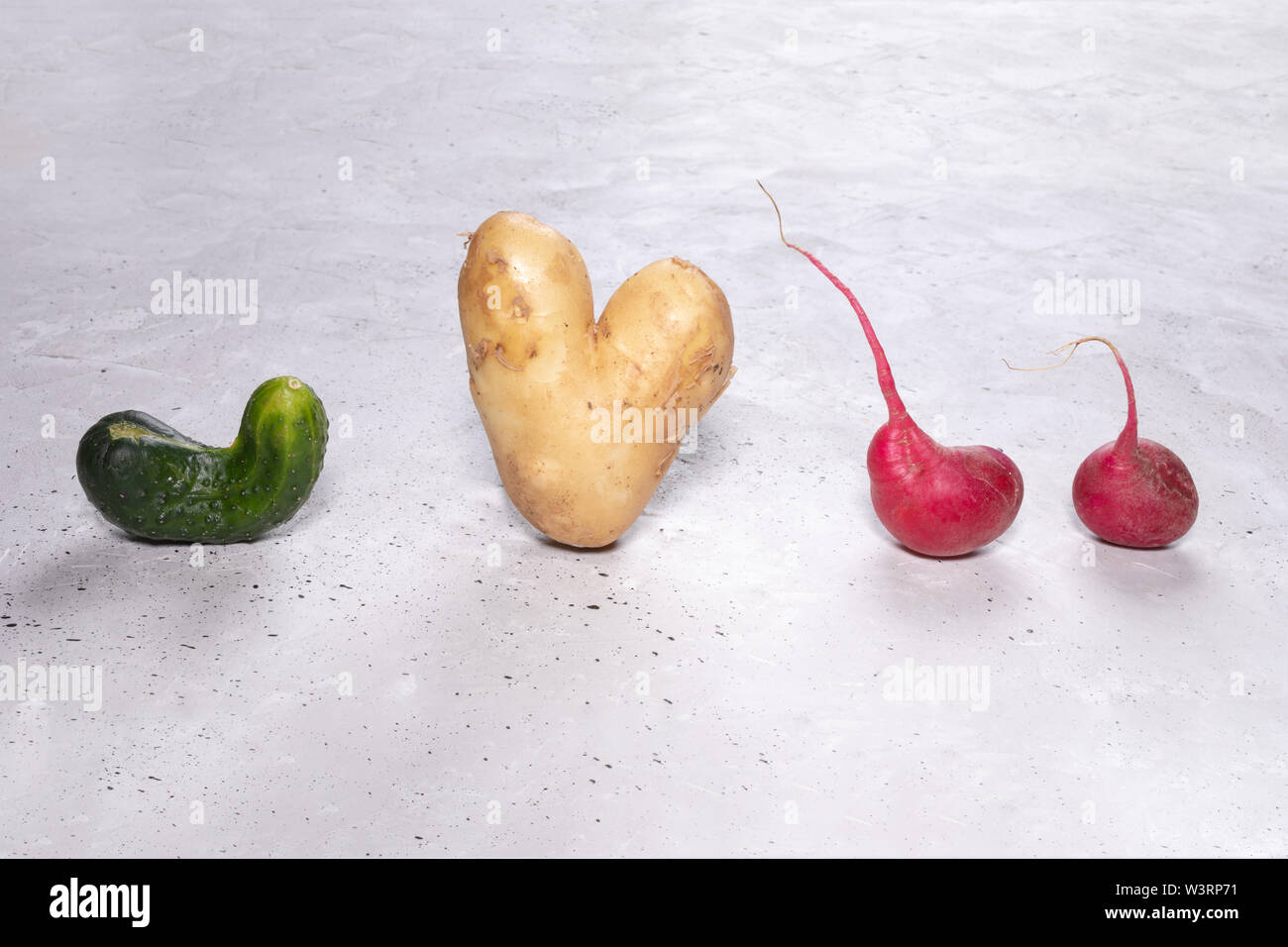 Four ugly vegetables: potato, cucumber and radish on grey concrete ...