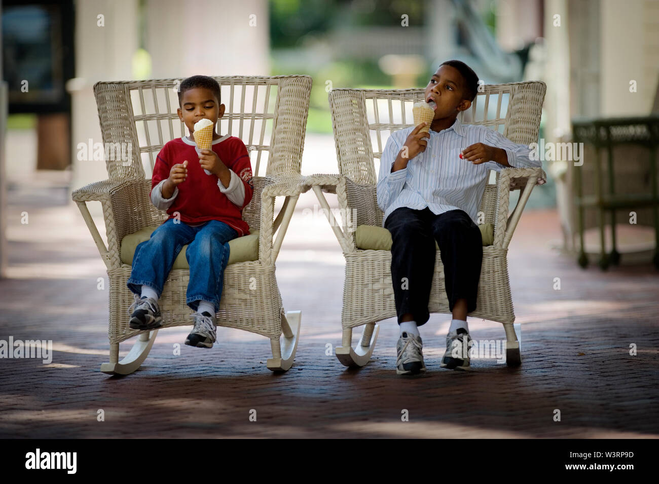Two boys sitting on outdoor rocking chairs eating ice-cream Stock Photo ...