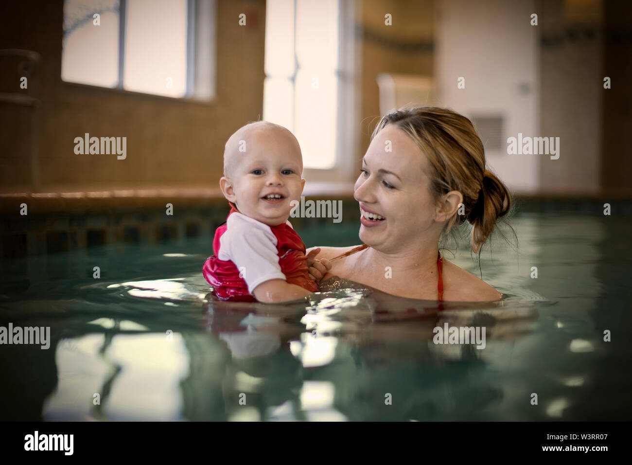 Young mother holding her baby in a swimming pool Stock Photo - Alamy