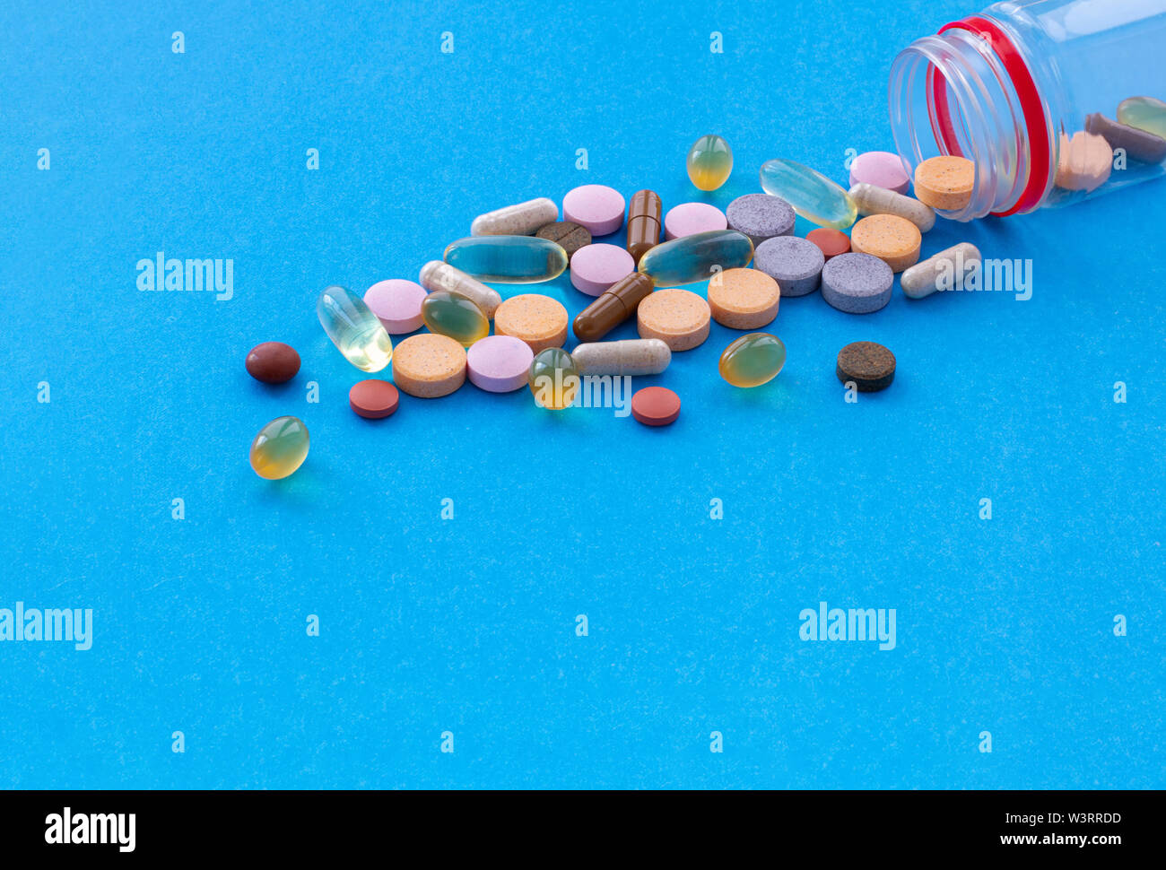 Multi-colored vitamins in capsules and tablets poured from a bottle, on ...