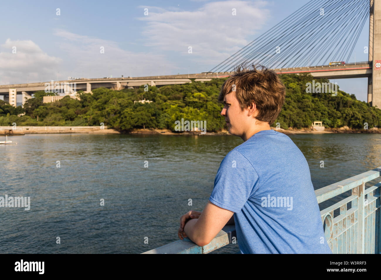 A young boy standing on the pier and watching the sea Stock Photo - Alamy