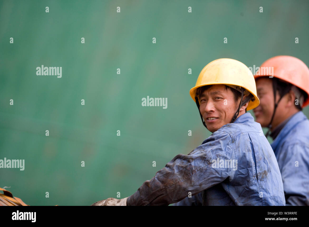 Portrait of a mid-adult construction worker on the back of a truck with ...