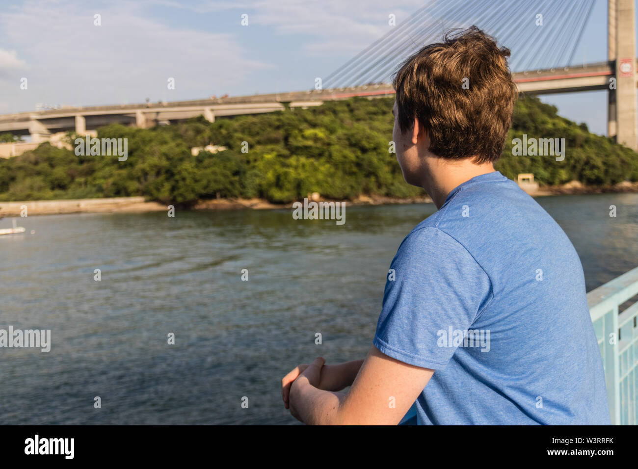 A young boy standing on the pier and watching the sea Stock Photo - Alamy