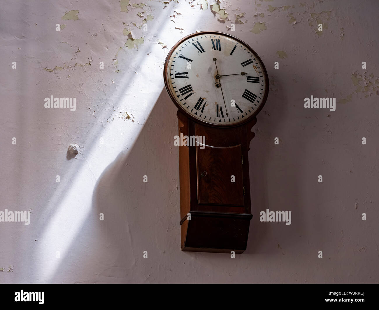 Vintage antique roman numerals clock on peeling paint wall with shaft ...