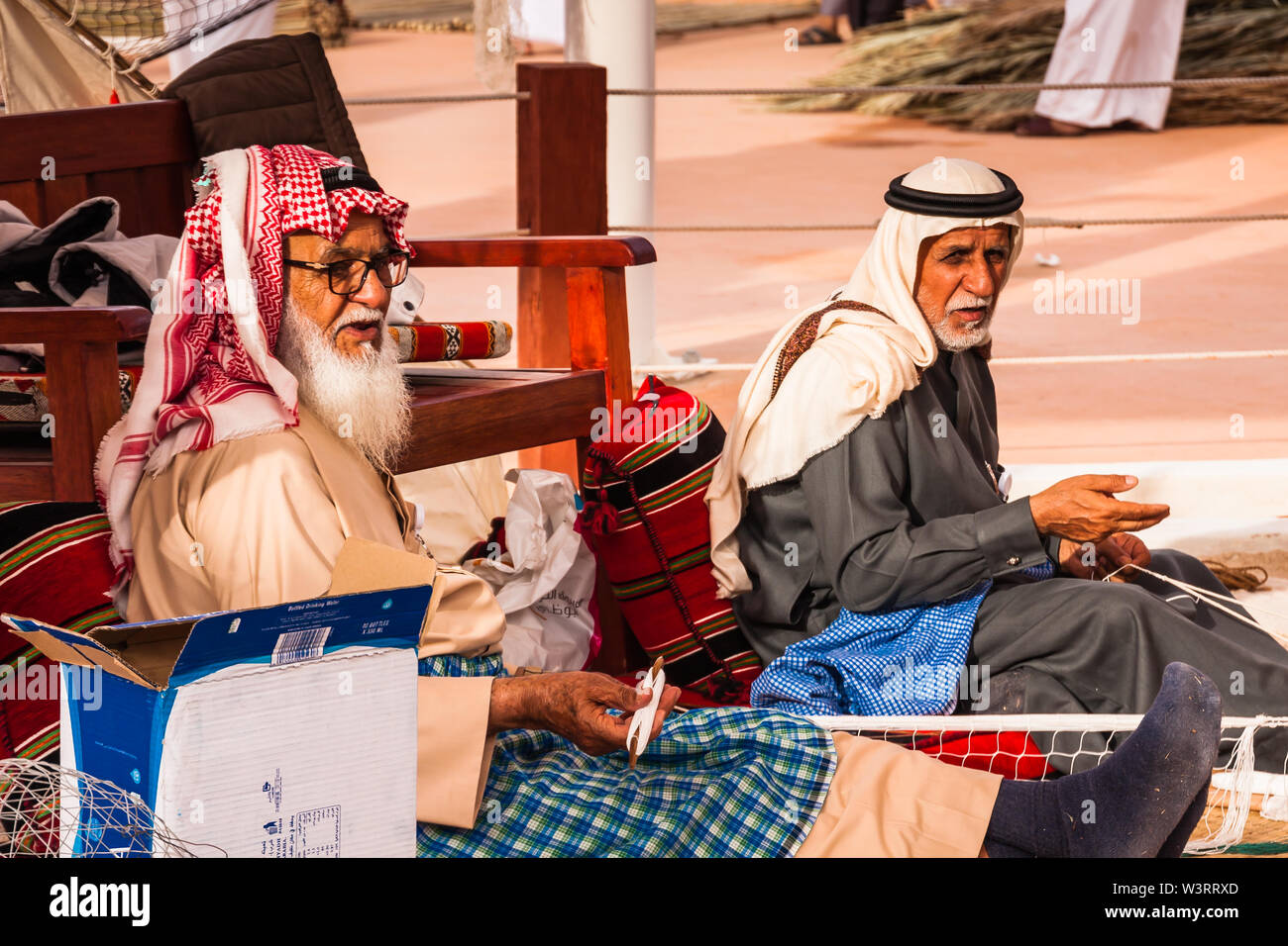 Two senior men in traditional clothing weaving a fishing net. The UAE ...