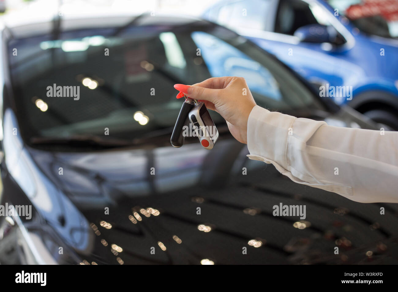 Dealer woman holding keys to a new car. Modern and prestigious vehicles ...