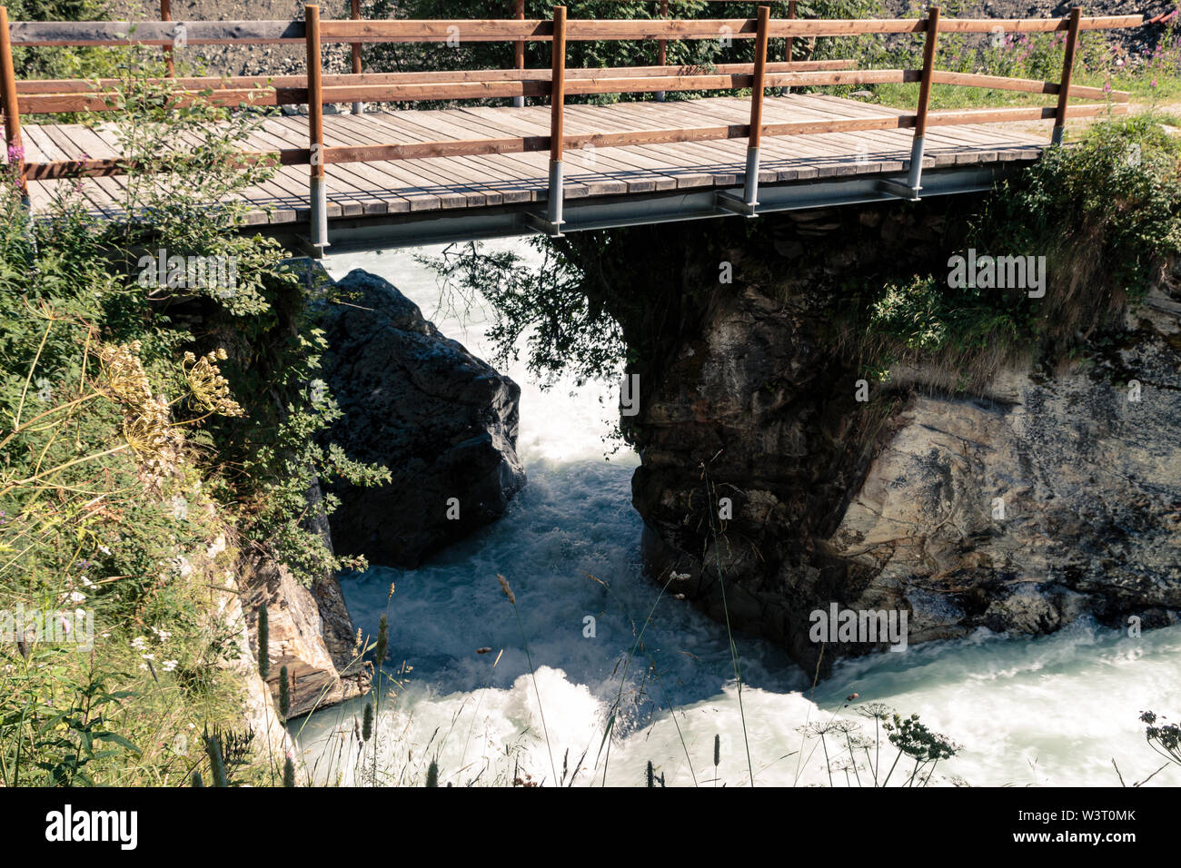 mountain river with white foam heads through narrow passage between ...