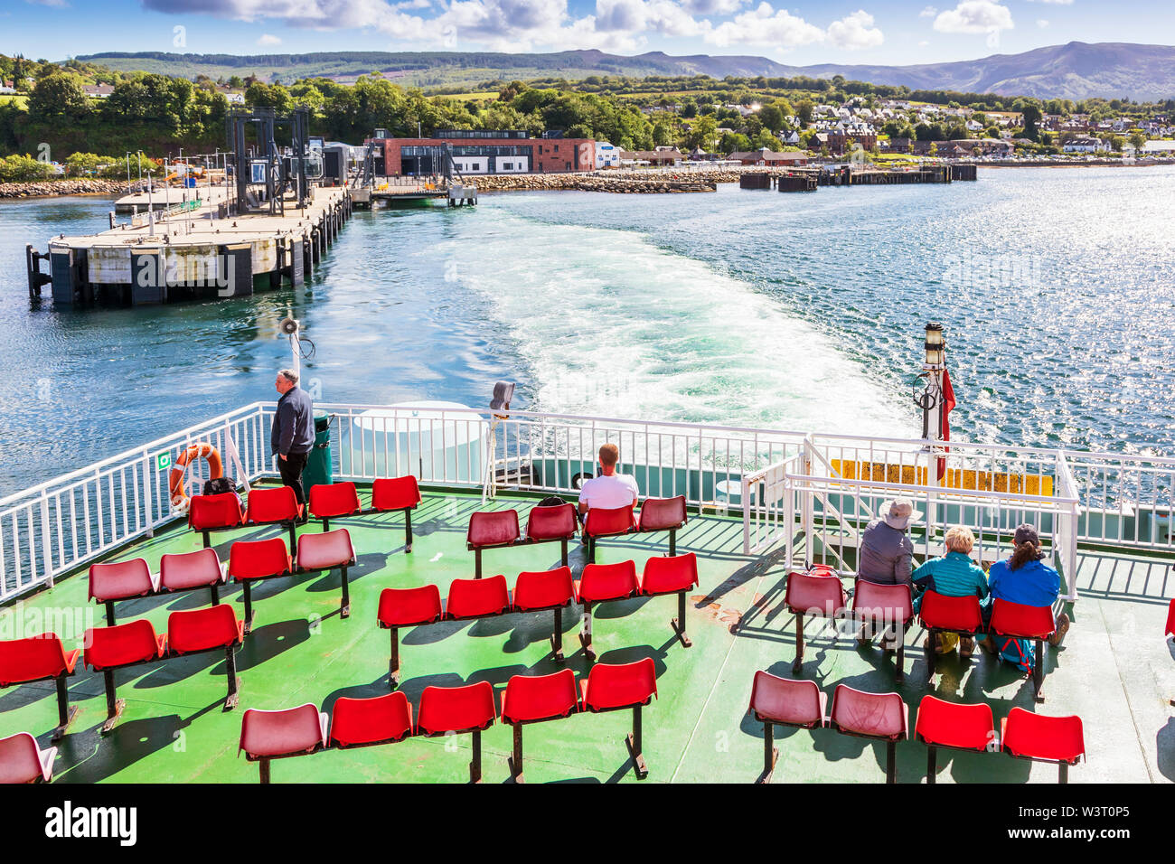 Passengers sitting at the stern of a Caledonian MacBrayne ferry leaving ...