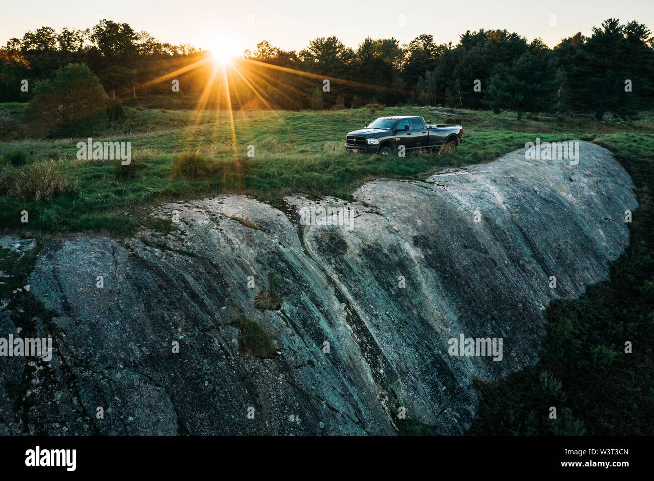 Pickup truck on rock at sunset in field Stock Photo - Alamy