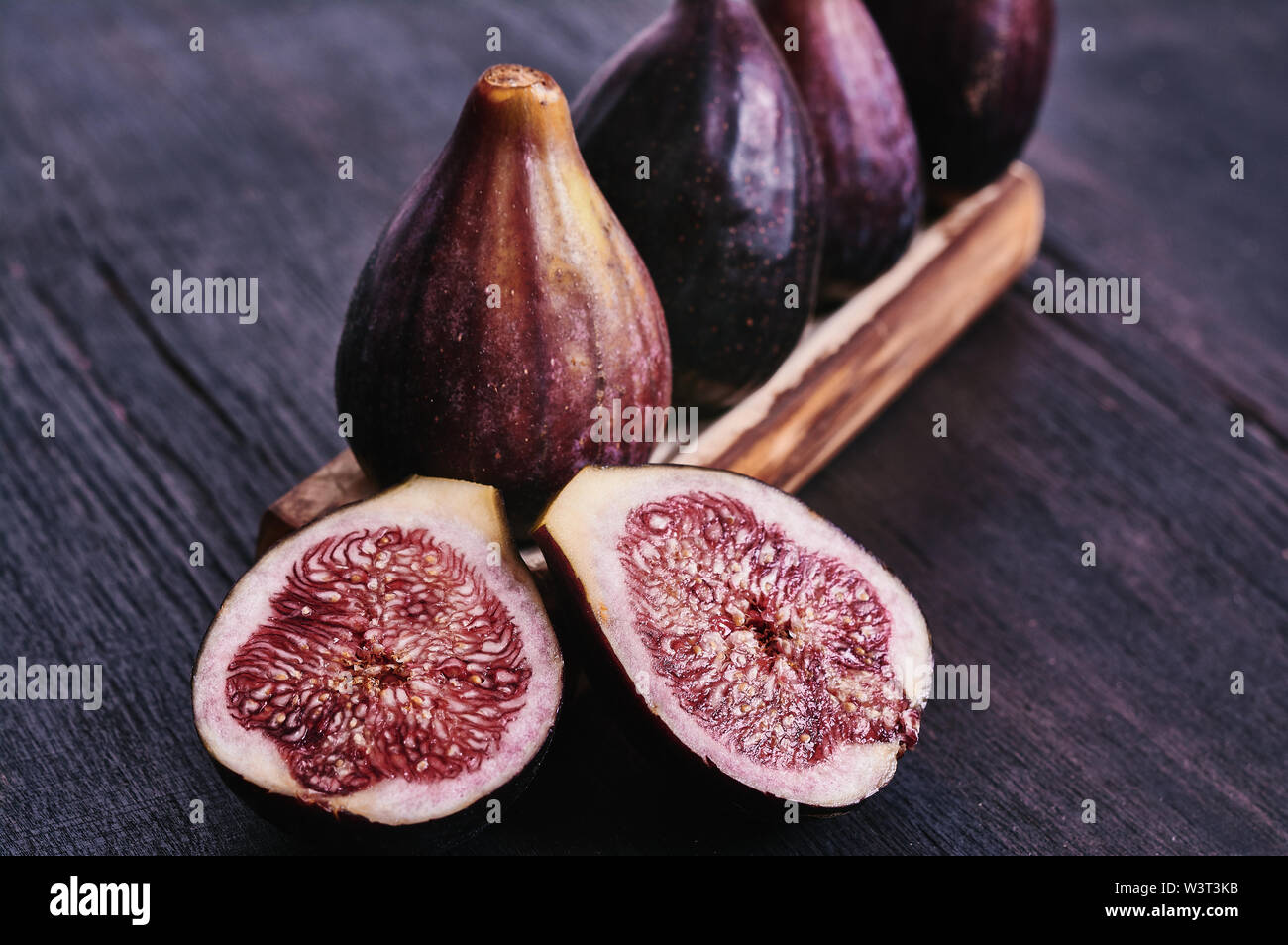 Figs isolated on dark wood background Stock Photo - Alamy