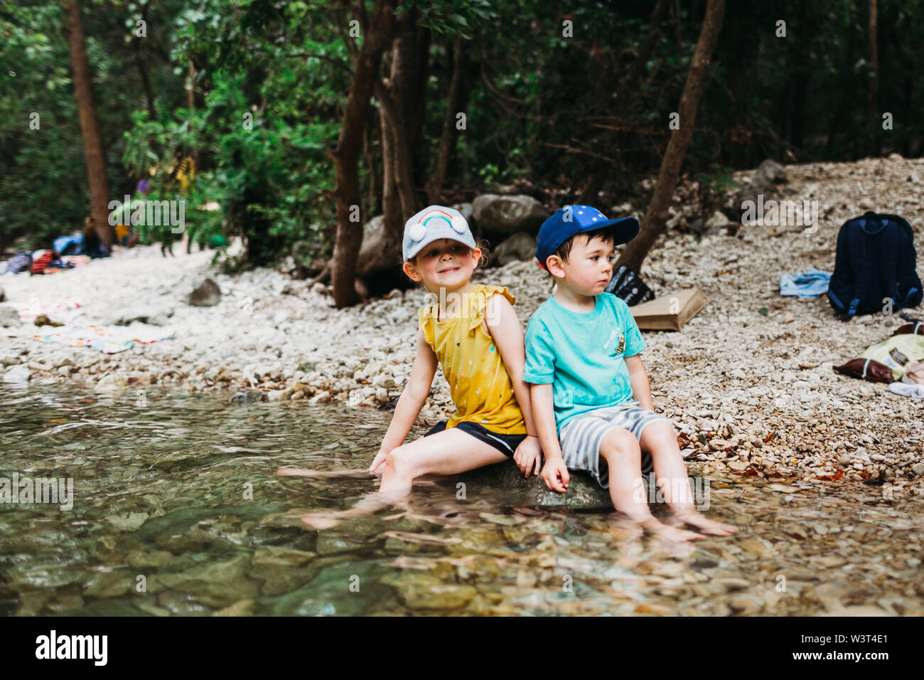 Young girl and boy sitting on rock in water at Barton Springs Stock ...