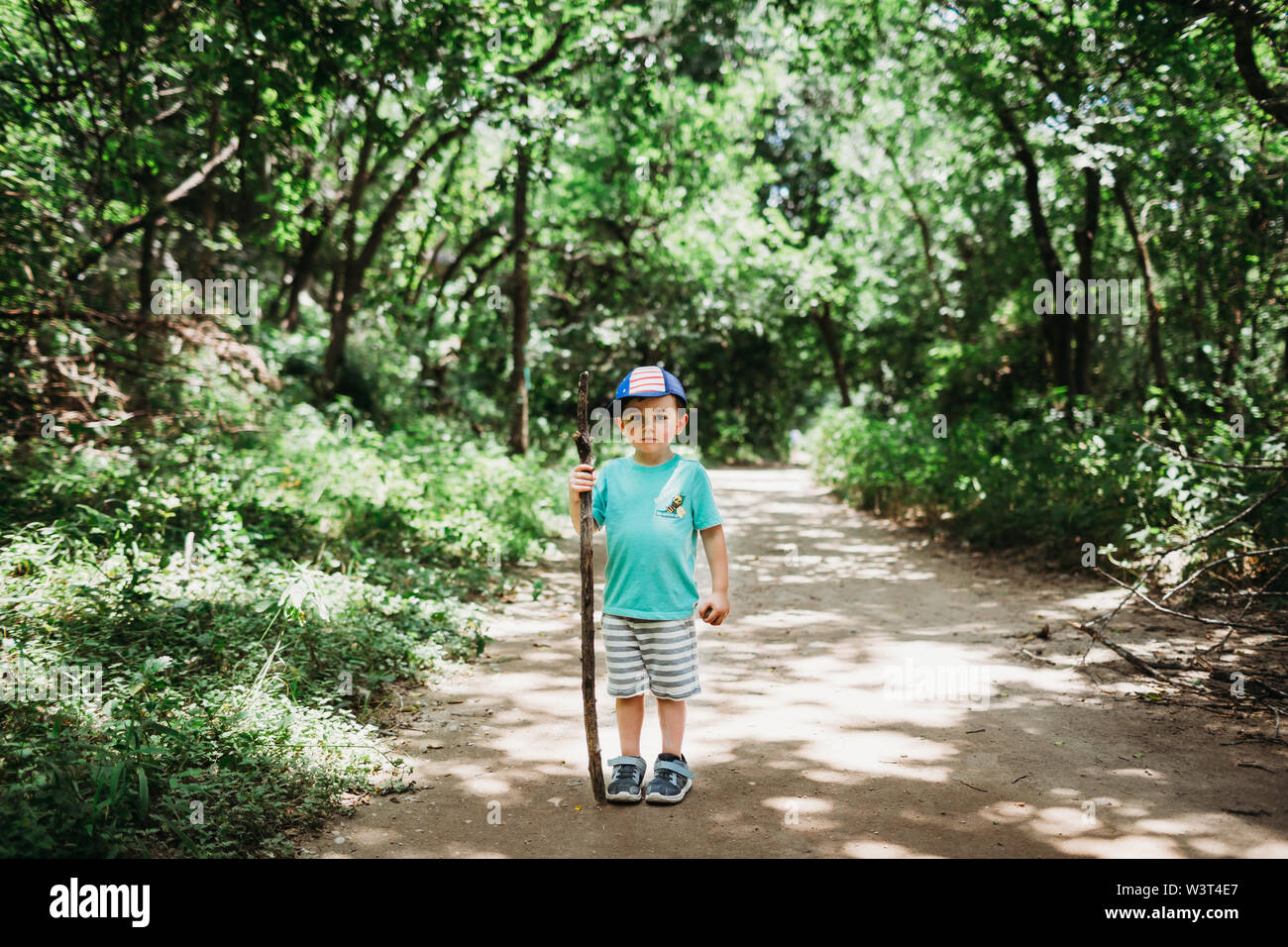 Young boy hiking and using walking stick with hat on Stock Photo - Alamy