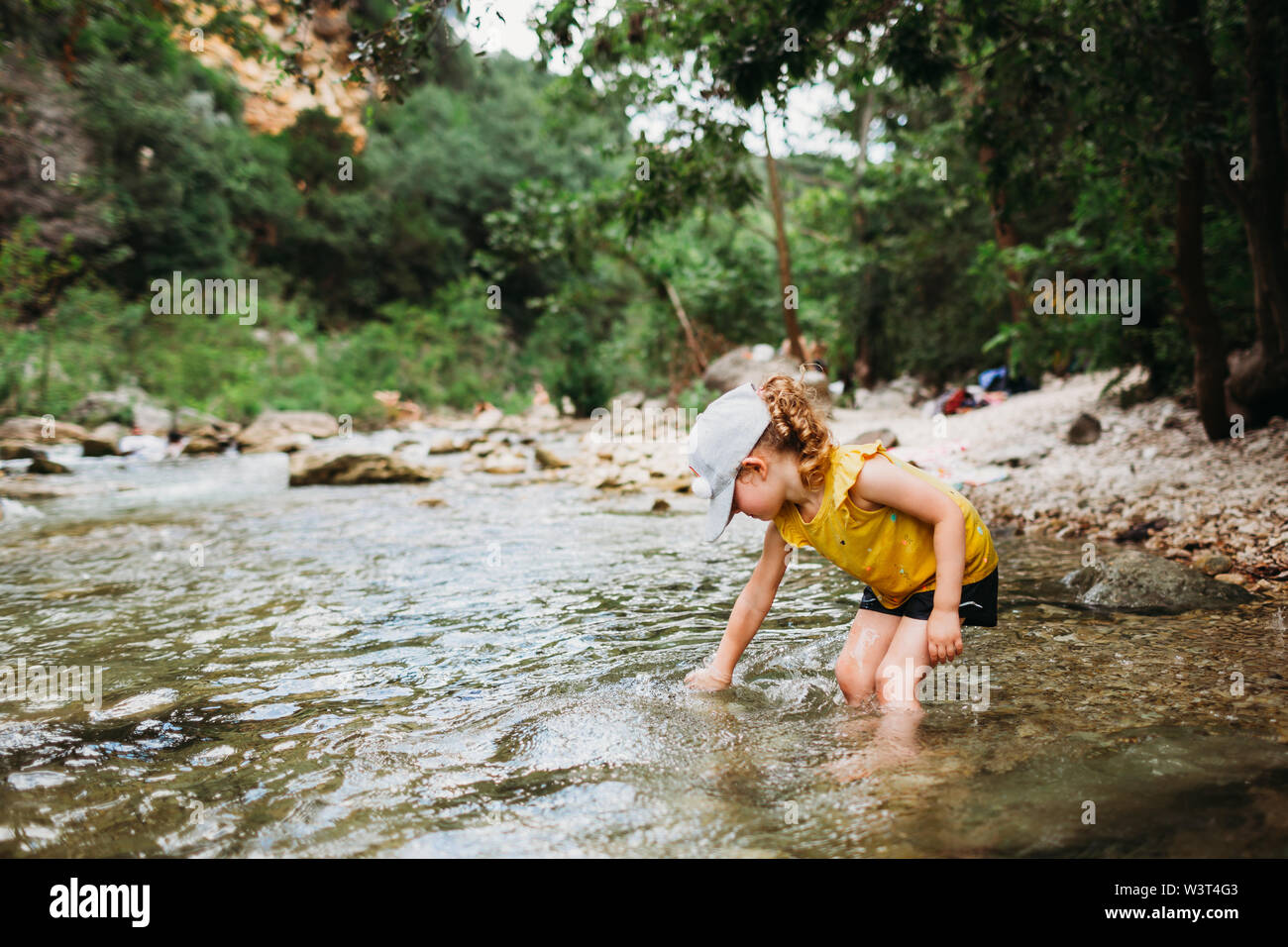 Young girl putting hand in water at Barton Springs on a hot summer day ...