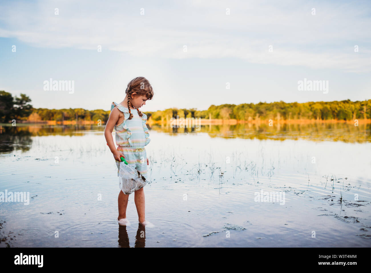 Young girl standing alone looking for fish in water at the lake Stock ...