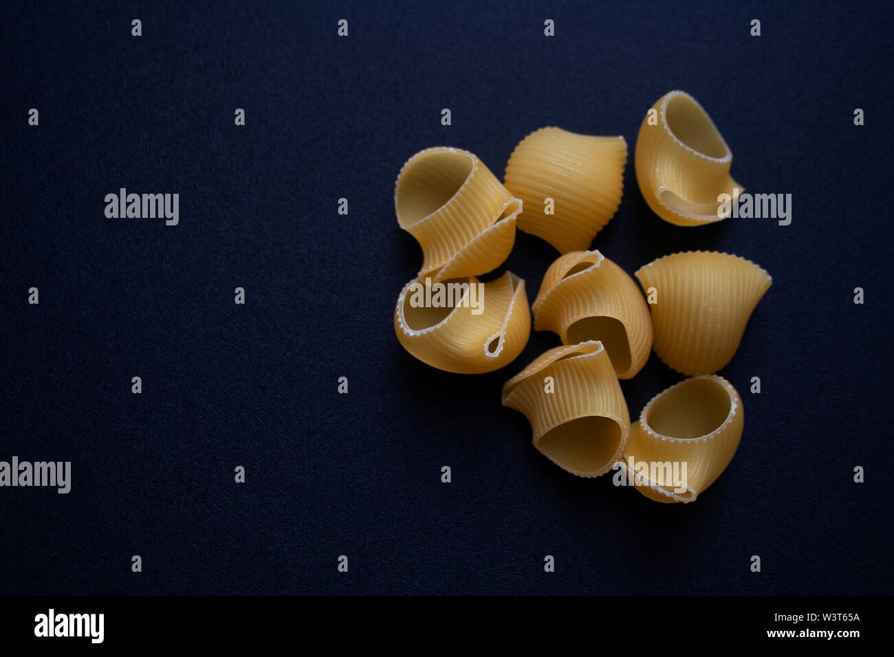 Heap of raw lumaconi also known as snail shell pasta isolated on black ...