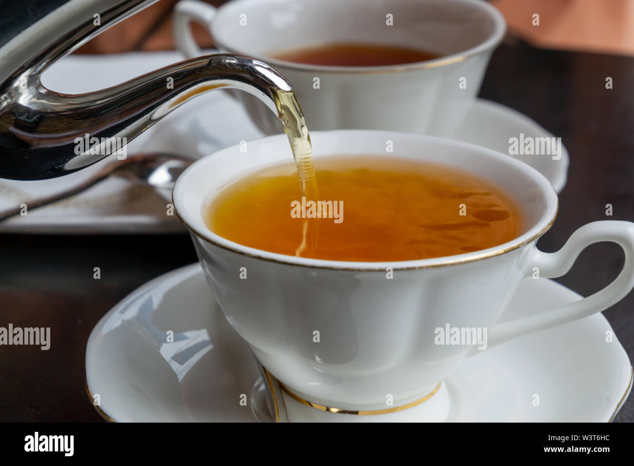 Teapot pouring herbal tea into a cup. The concept of healthy eating ...