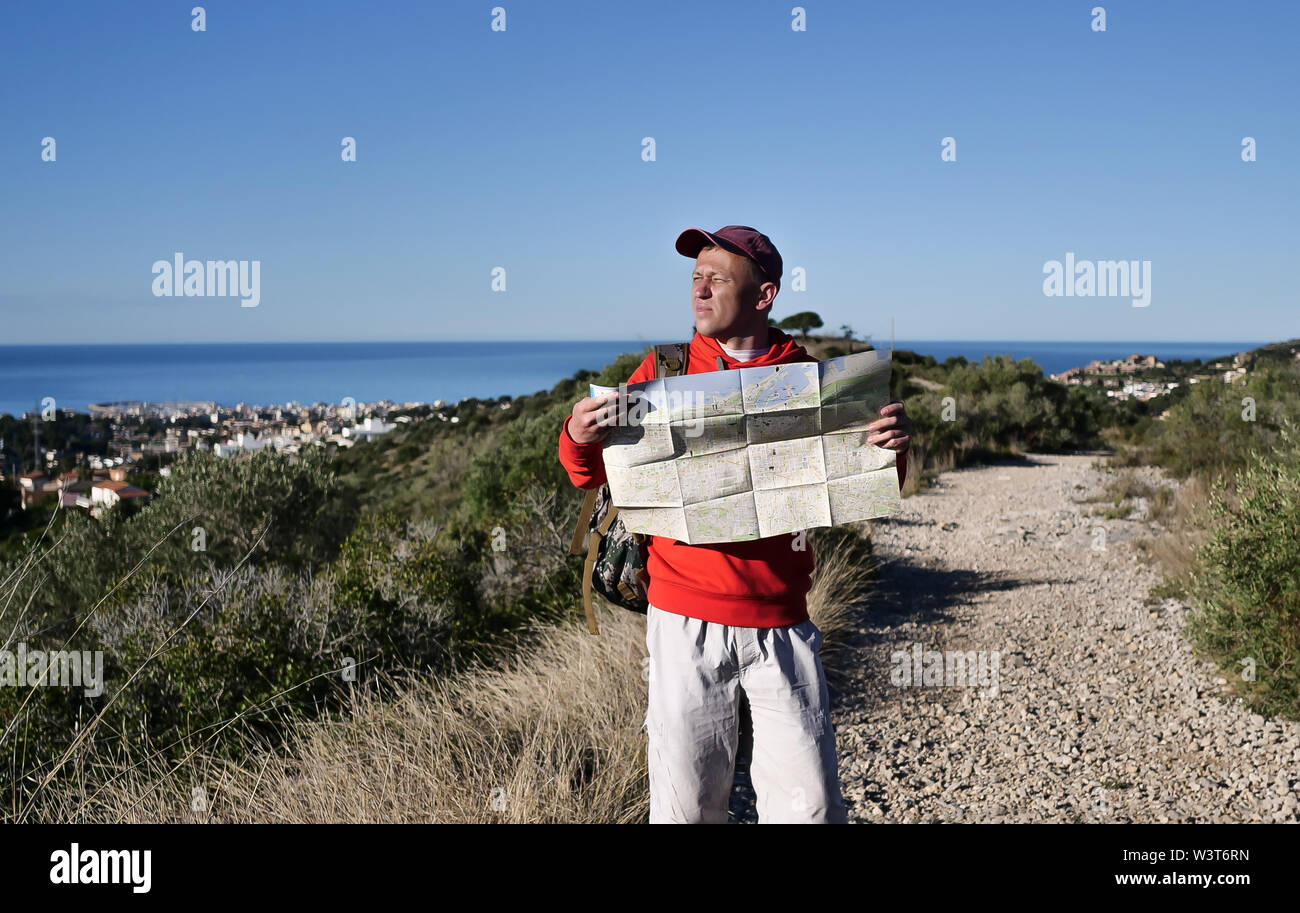 Tourist guy is standing on a hill path and holding a map Stock Photo ...