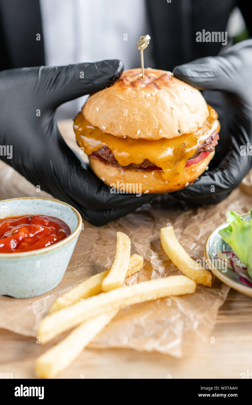 Young man in business suit and black gloves eating delicious juicy ...