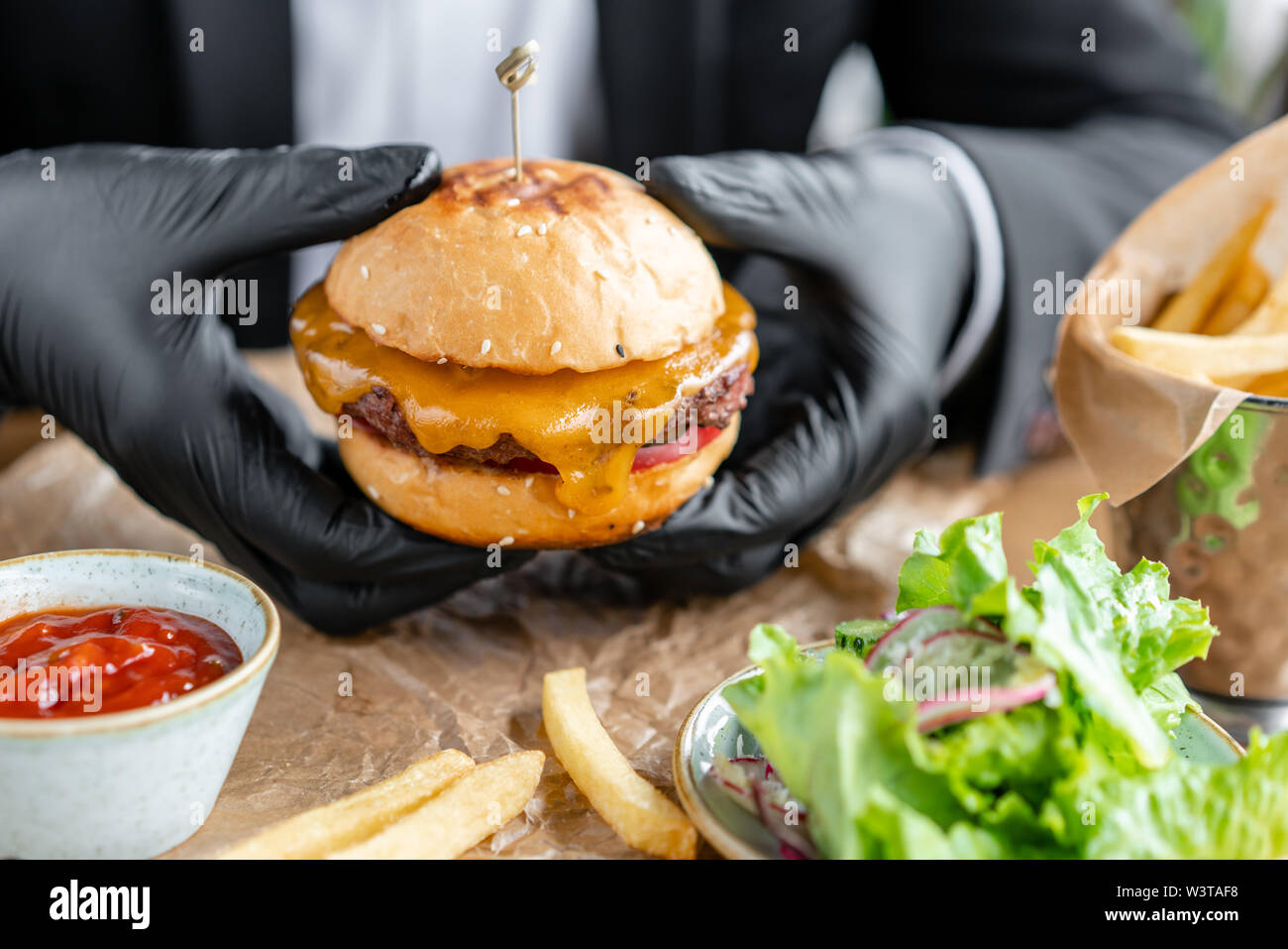 Young man in business suit and black gloves eating delicious juicy ...
